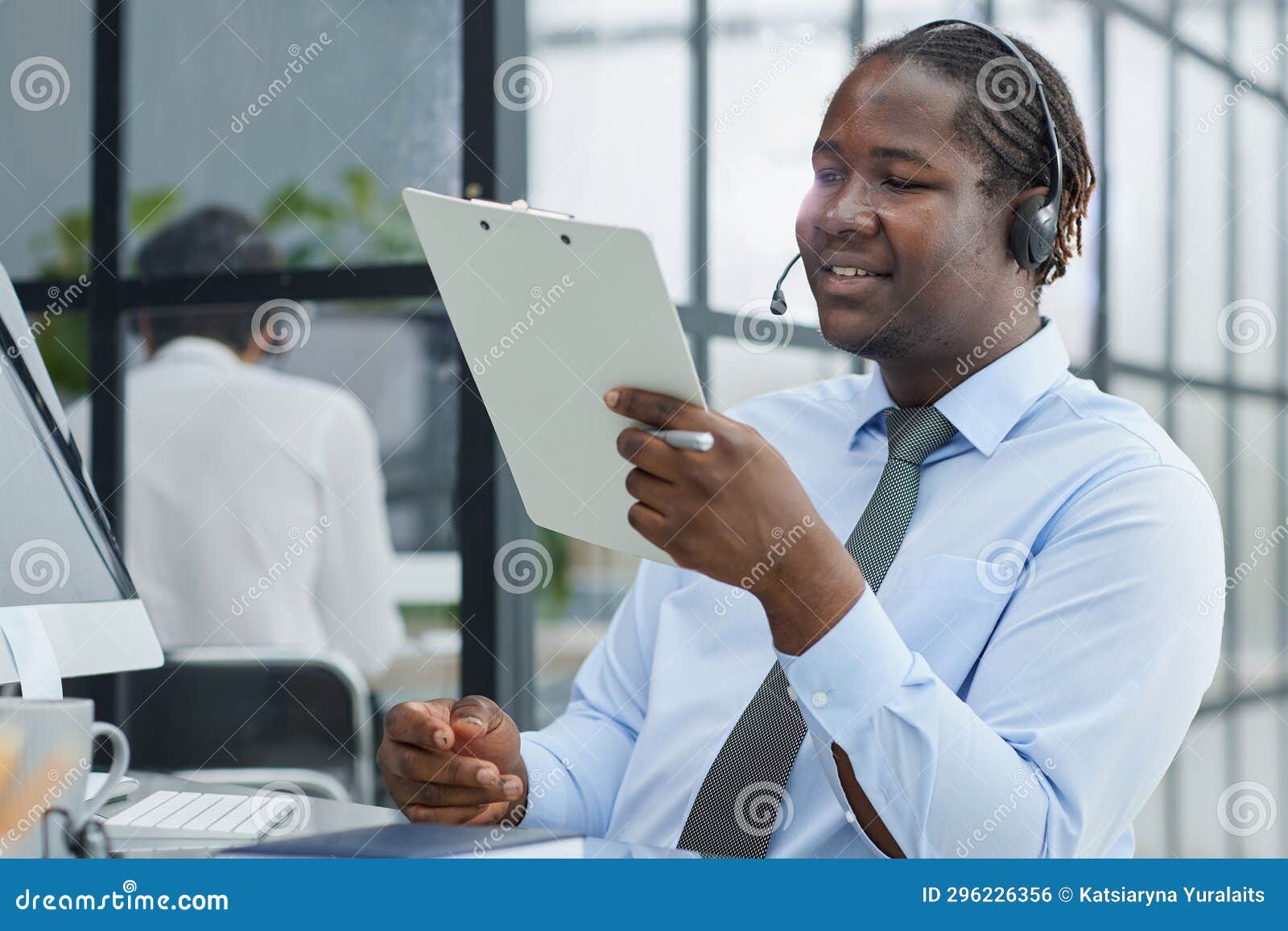 A Man at a Computer in a Call Center Talking Using Headphones with a ...