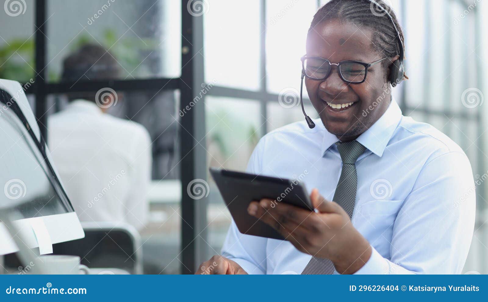 A Man at a Computer in a Call Center Talking Using Headphones with a ...