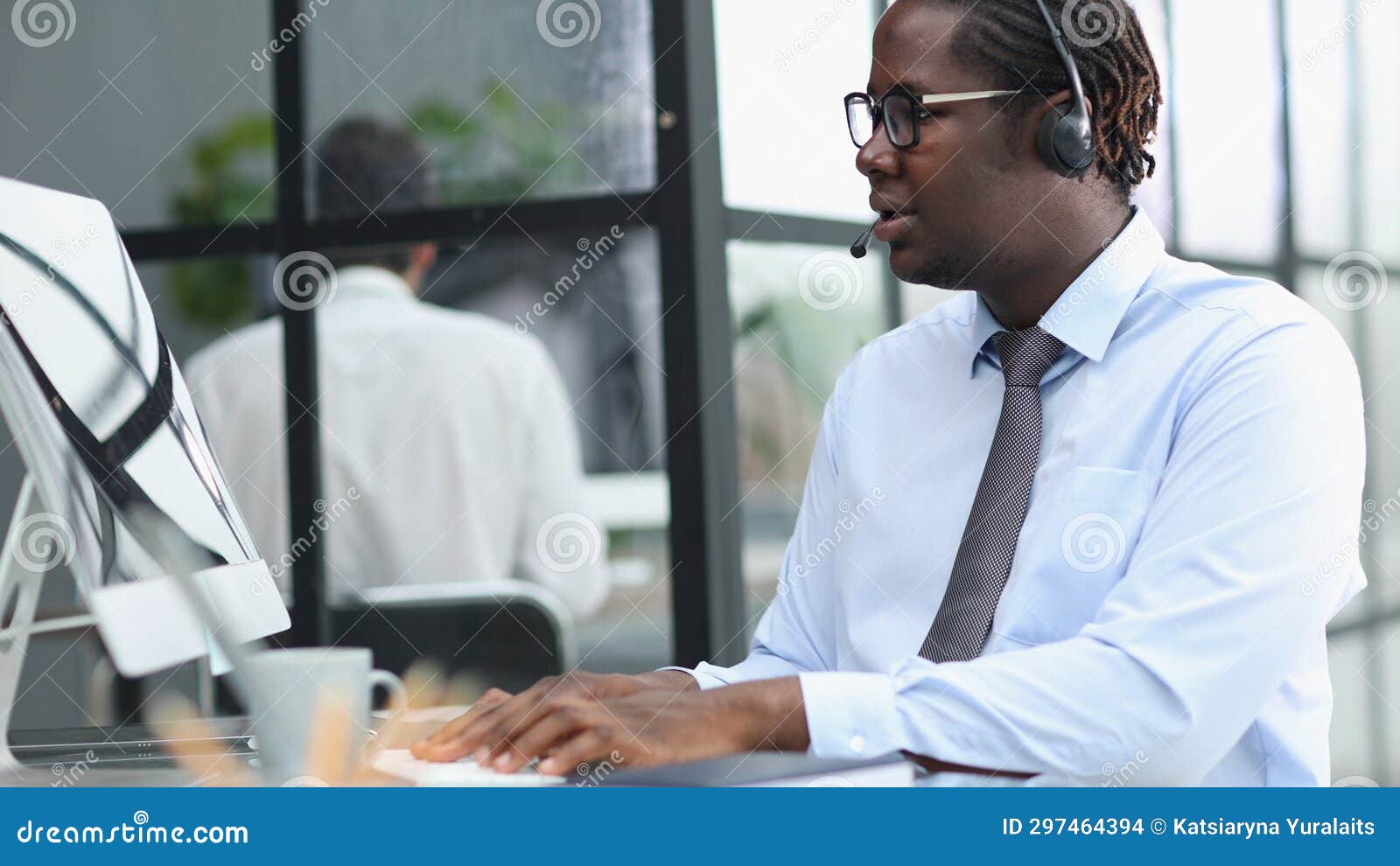 A Man at a Computer in a Call Center Talking Using Headphones with a ...