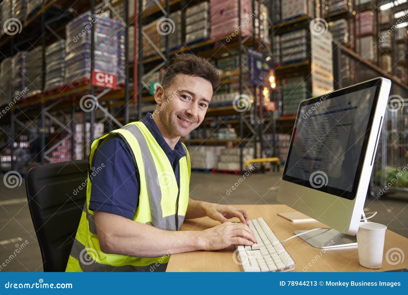Man at Computer in on-site Warehouse Office Looks To Camera Stock Image ...