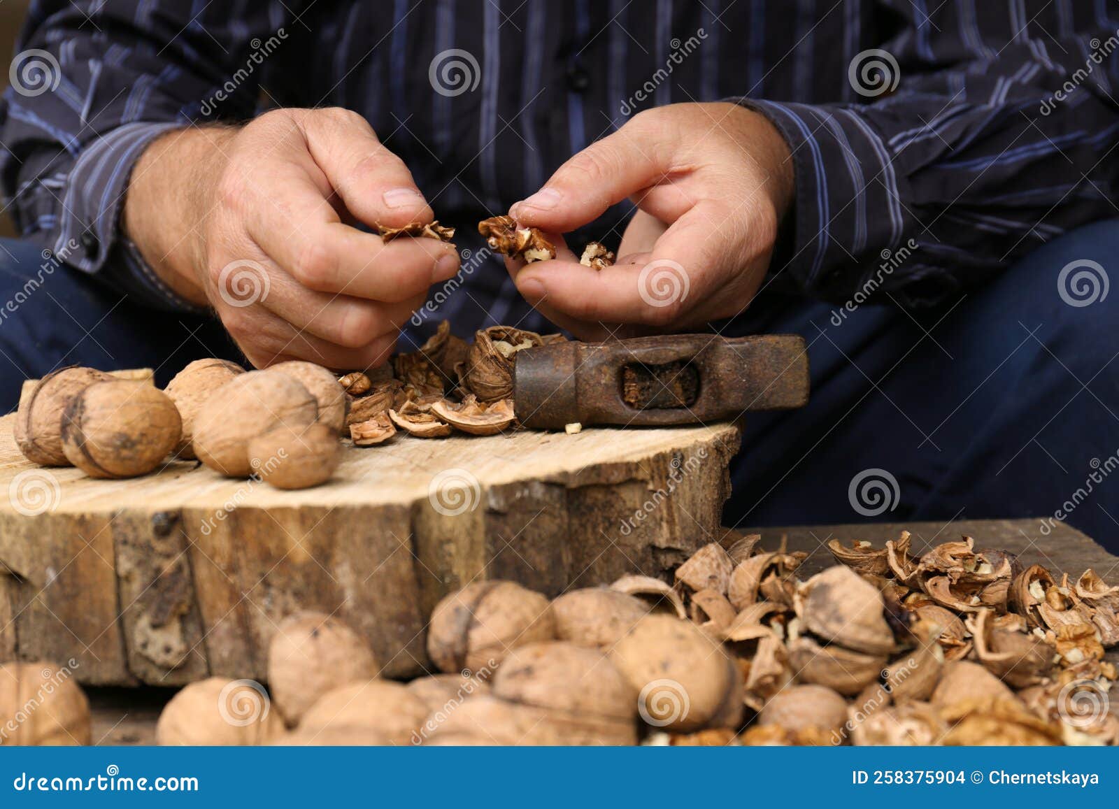 Man Cracking Walnuts with Hammer at Wooden Table, Closeup Stock Photo ...
