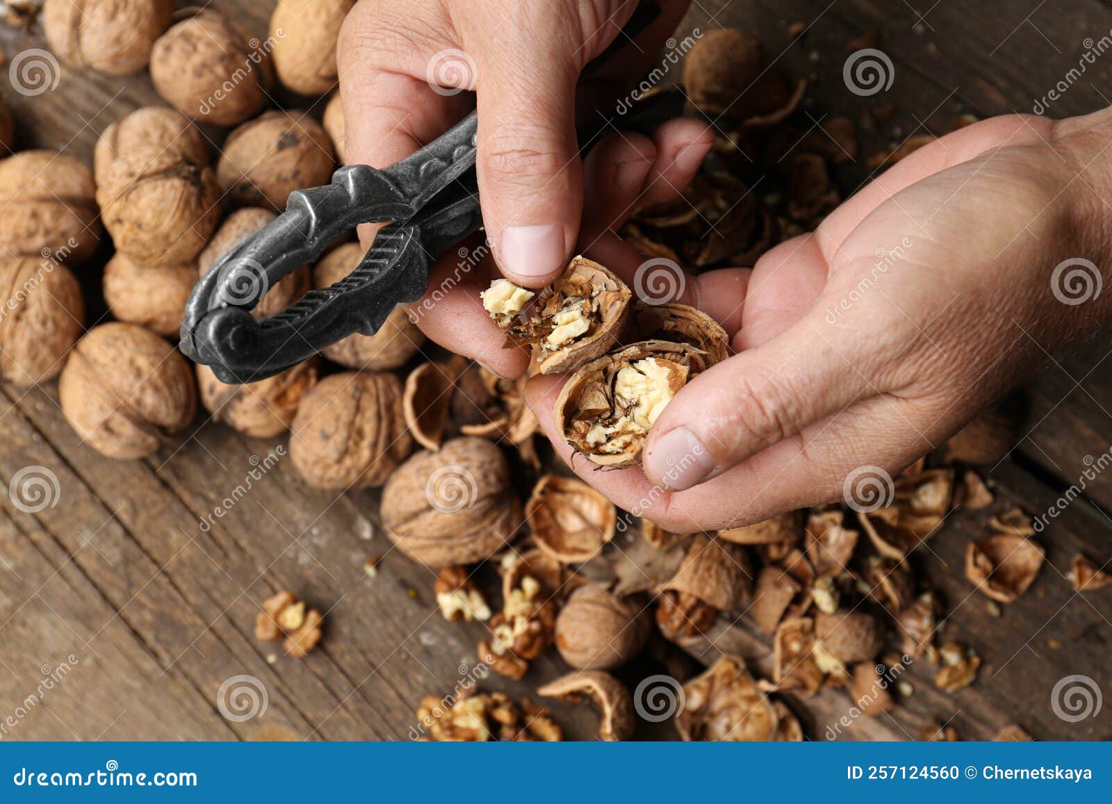 Man Cracking Walnuts at Wooden Table, Closeup Stock Photo - Image of ...