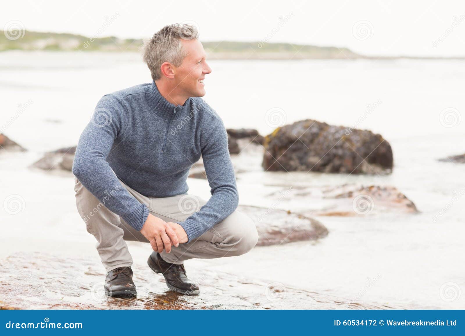 Man Crouched Down on a Large Rock Stock Photo - Image of waves ...
