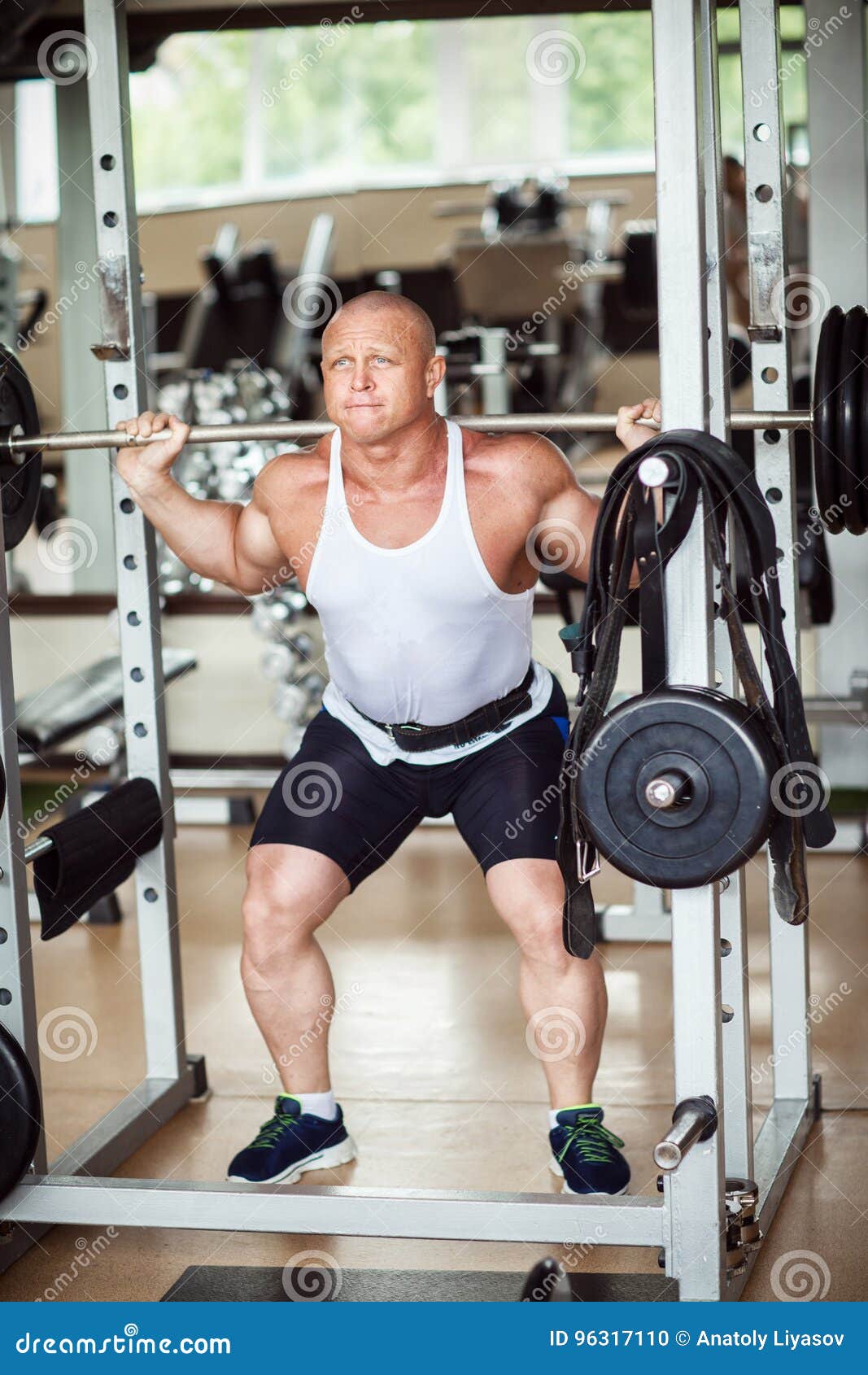The Man Crouches with a Barbell Stock Photo - Image of hanging ...
