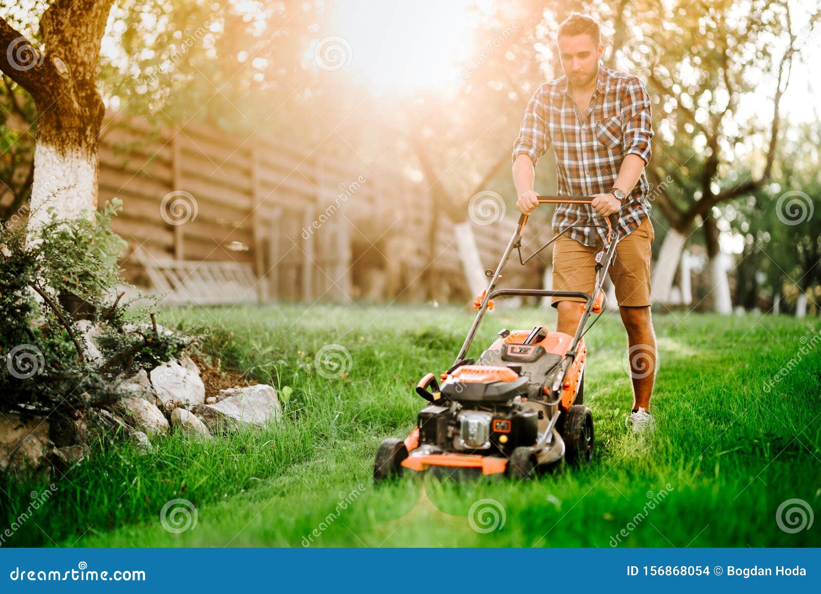 Man Cutting the Grass in Garden Using Lawn Mower and Professional ...