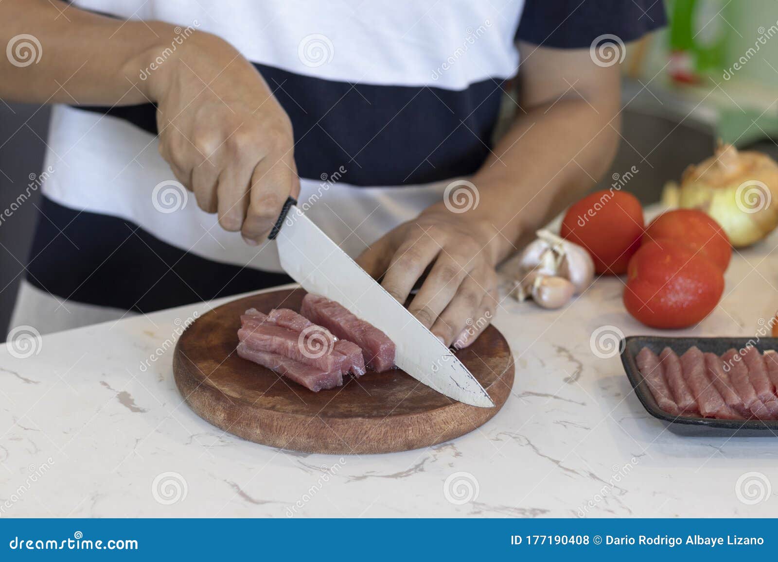 Man Cutting a Piece of Beef White a Knife on a White Kitchen Table with ...