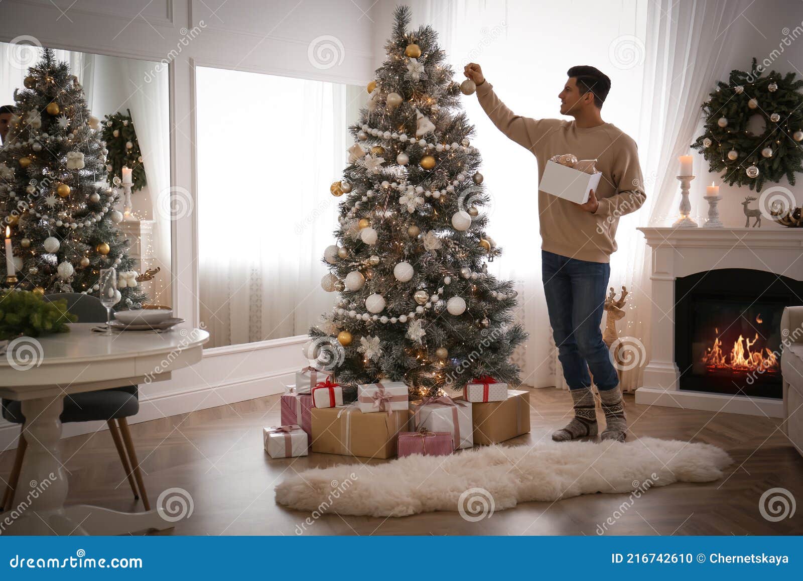 Man Decorating Christmas Tree in Beautiful Room Interior Stock Photo ...