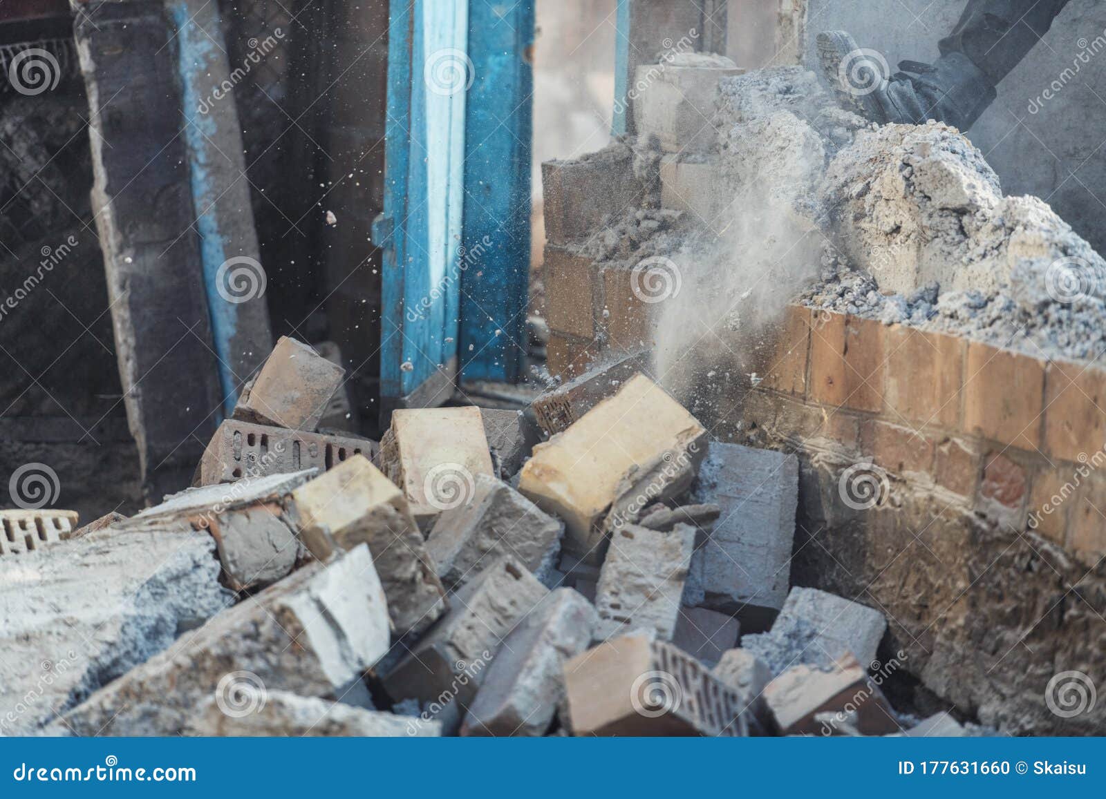 A Man Destroys a Wall of Old House. Dust and Bricks in Action Stock ...