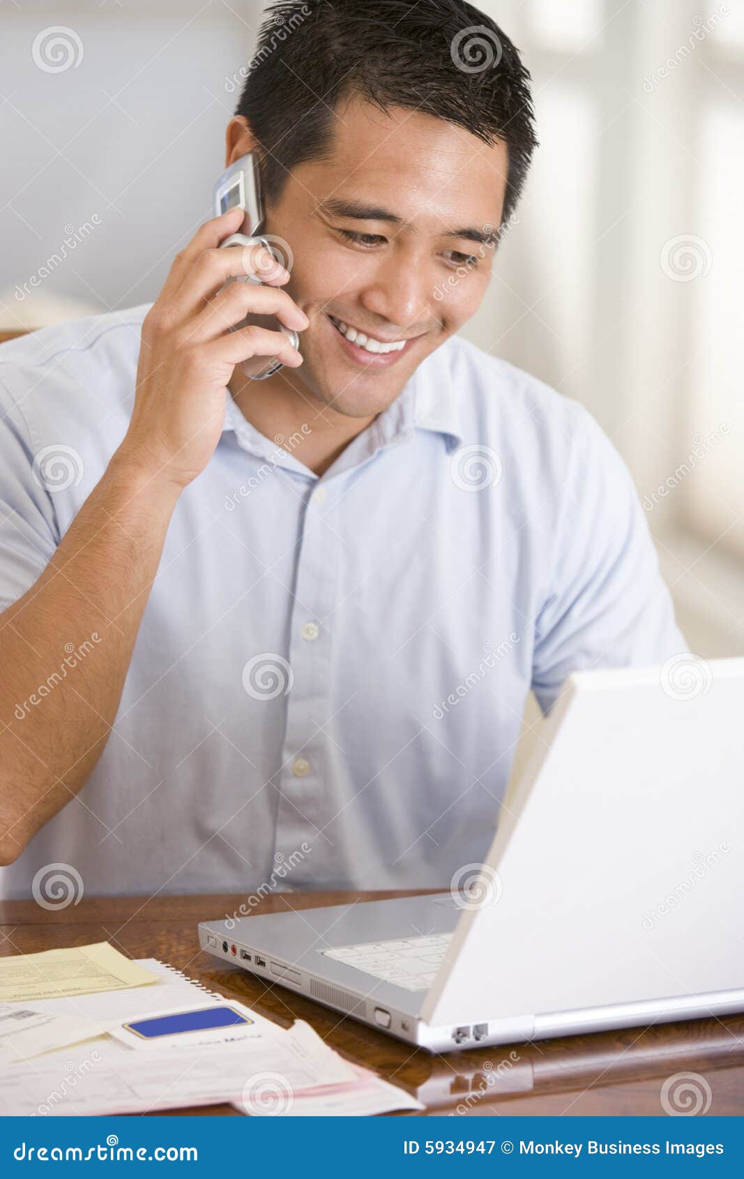 Man in Dining Room on Cellular Phone Using Laptop Stock Image - Image ...