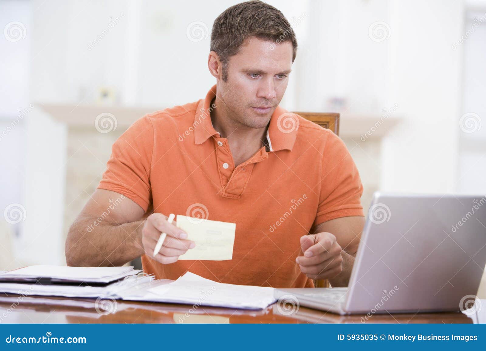 Man in Dining Room with Laptop Holding Paperwork Stock Image - Image of ...