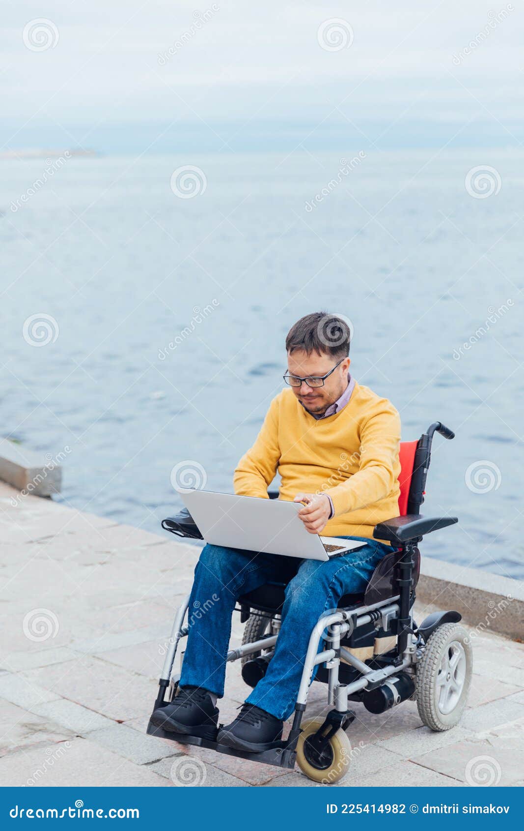A Man with Disabilities in a Wheelchair Works on a Computer on the ...