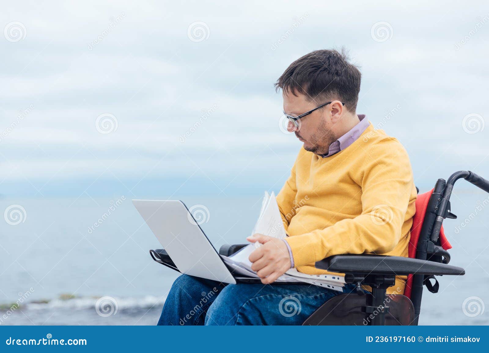 A Man with Disabilities in a Wheelchair Works on a Laptop Remotely ...