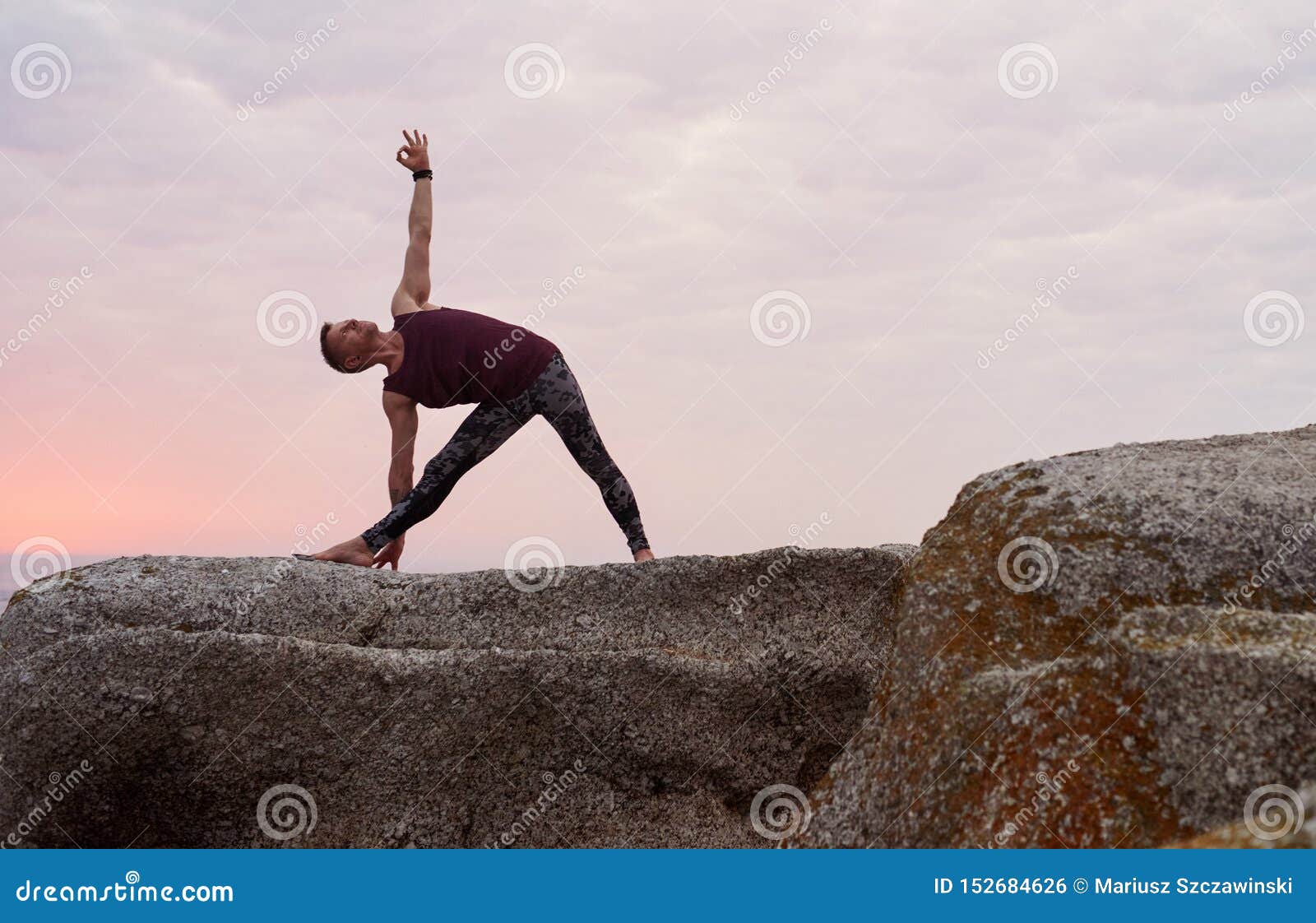 Man Doing the Triangle Pose on Some Rocks at Dusk Stock Photo - Image ...
