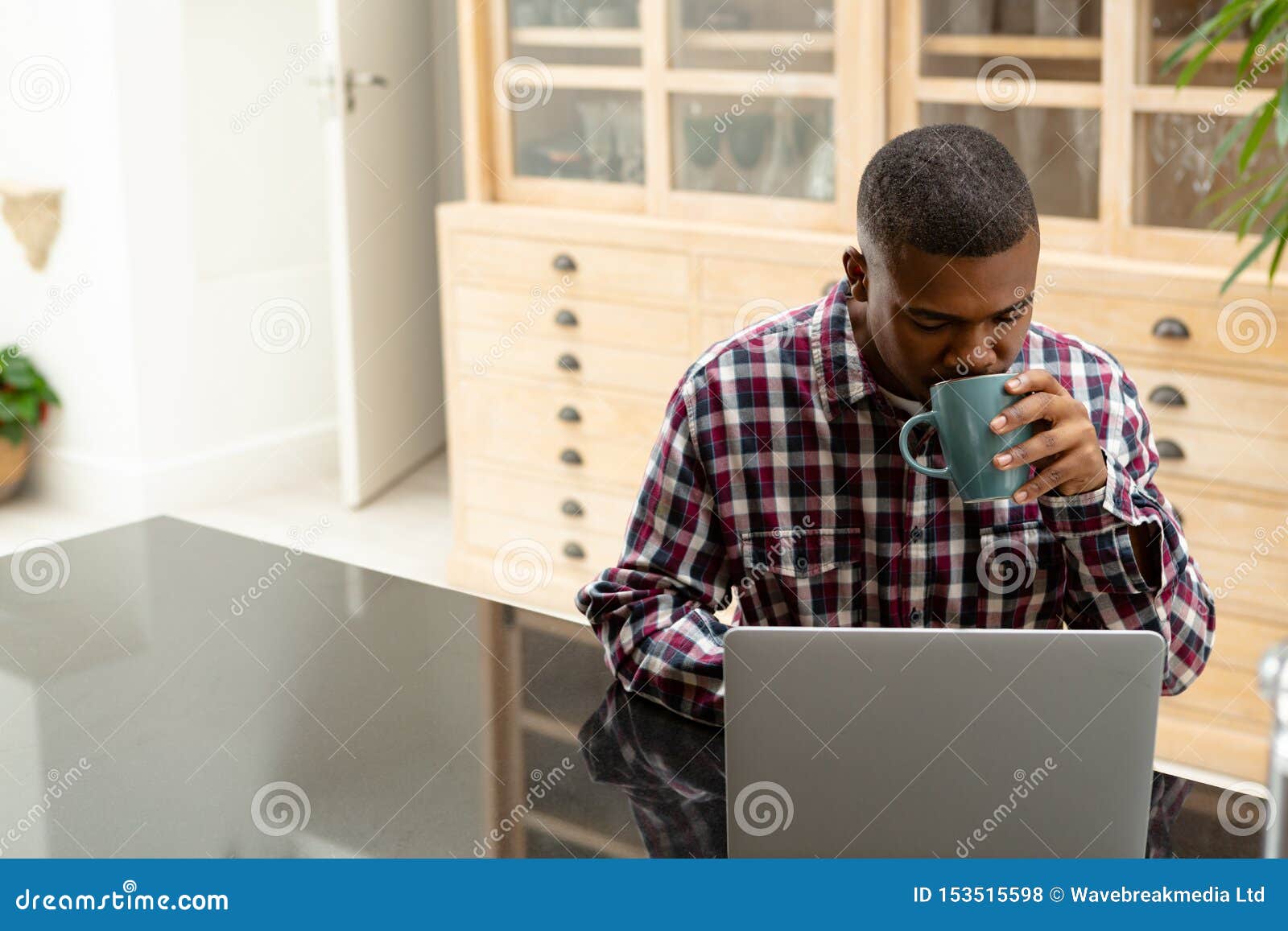 Man Drinking Coffee while Using Laptop on Worktop in Kitchen Stock ...