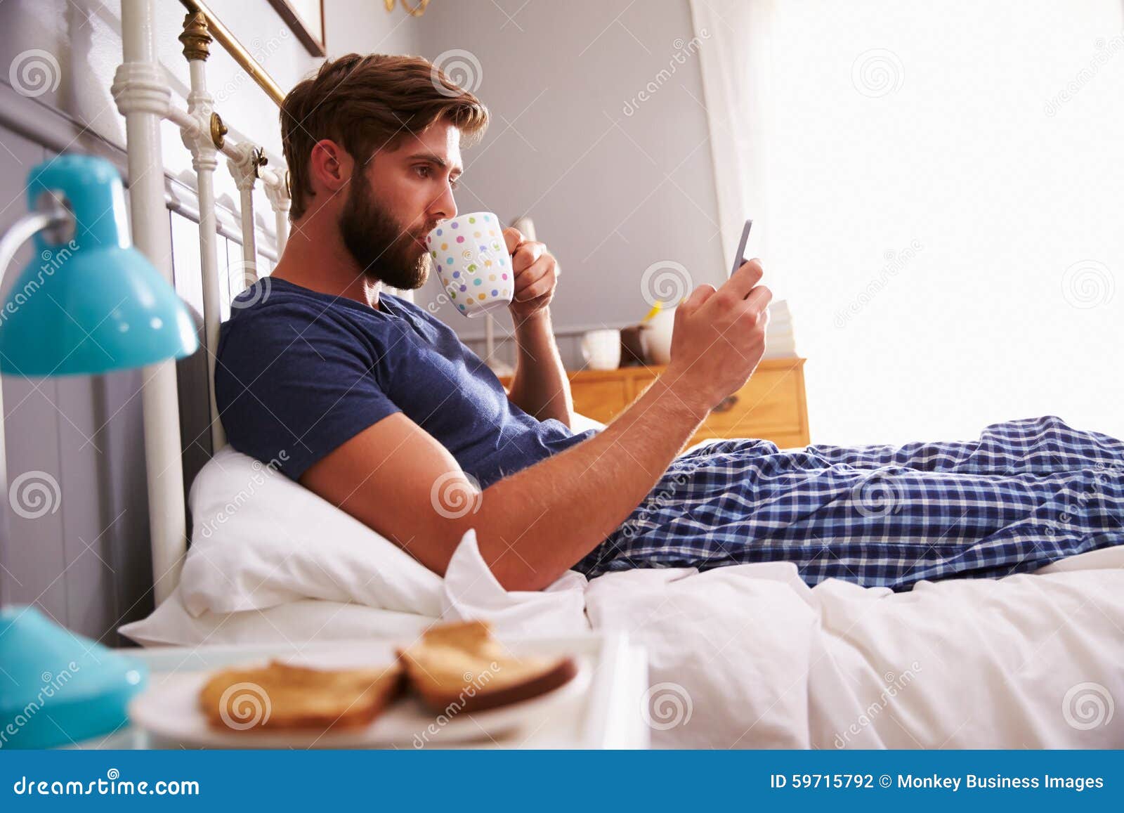 Man Eating Breakfast in Bed Whilst Using Mobile Phone Stock Photo ...