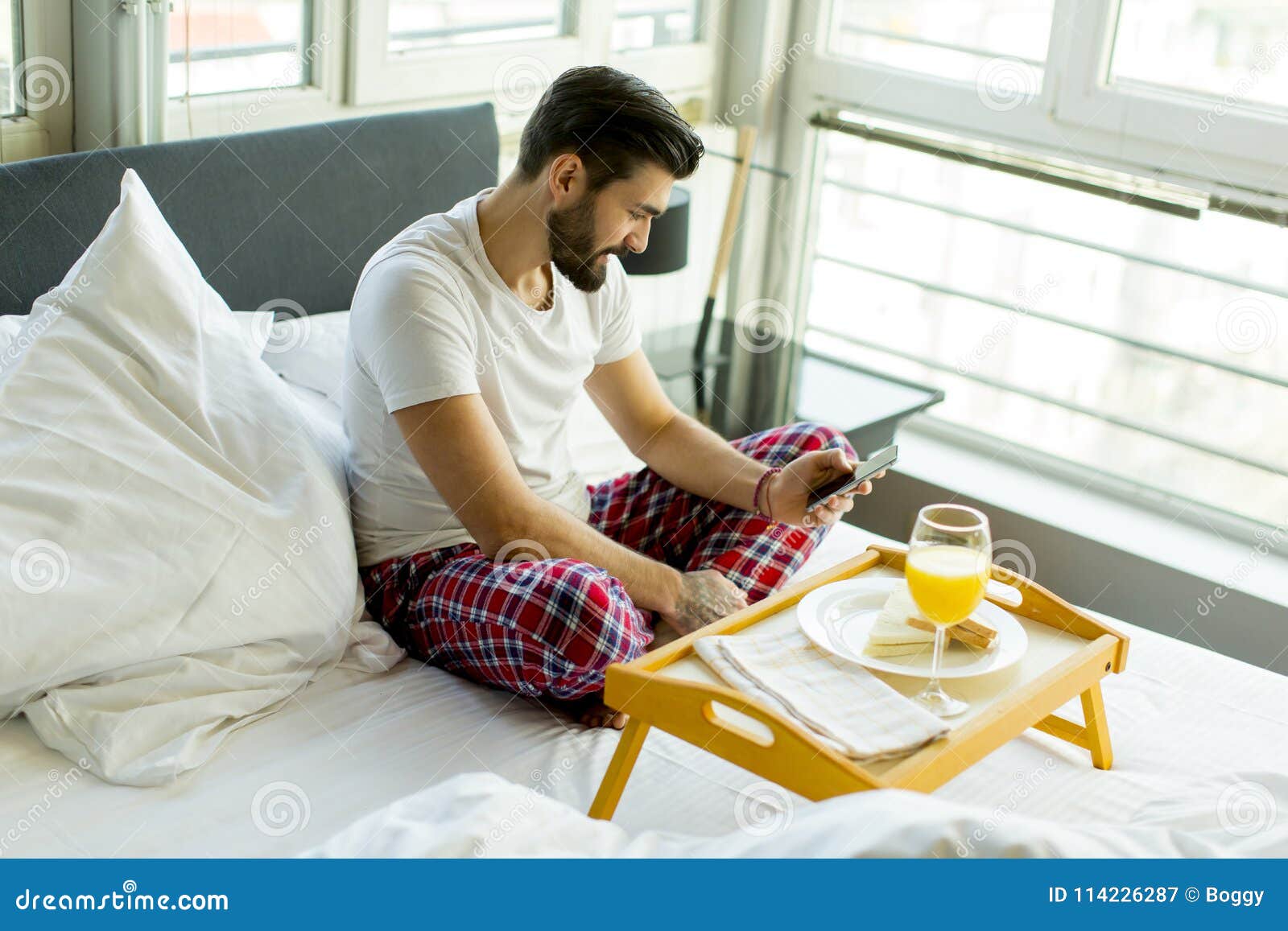 Man Eating Breakfast in Bed Whilst Using Mobile Phone Stock Image ...