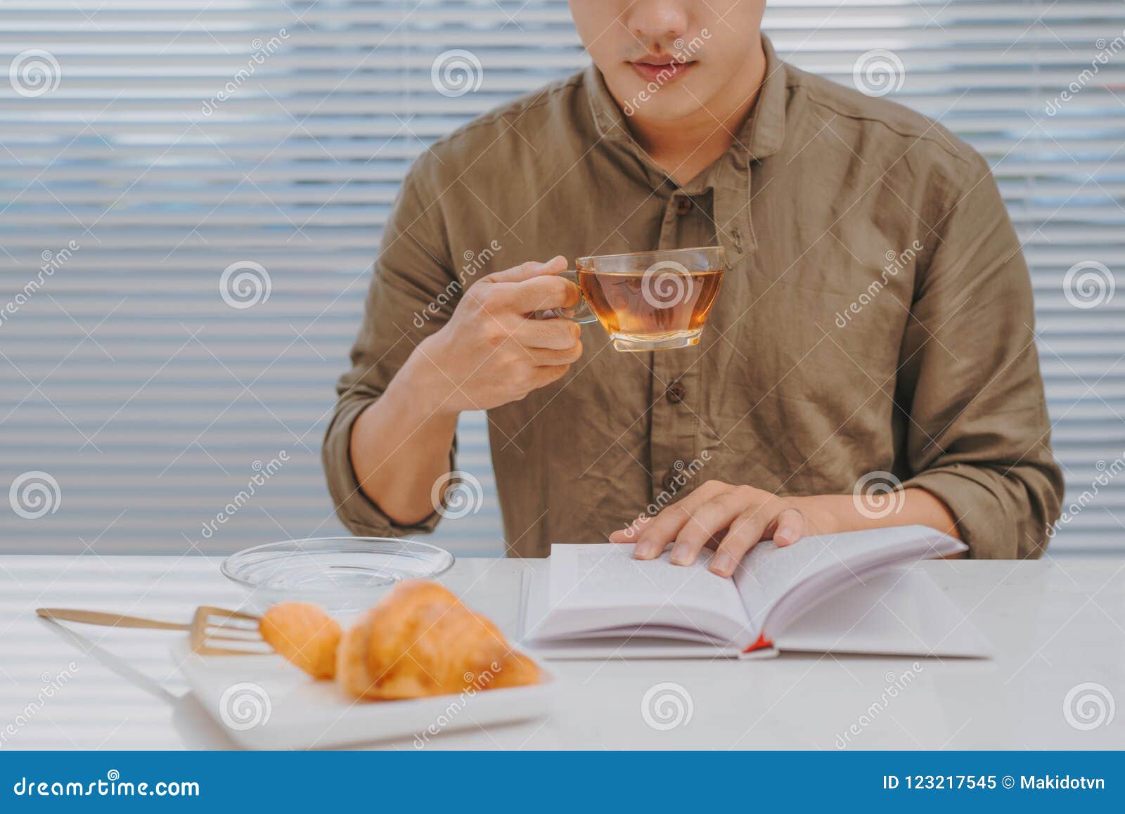 Man Eating Breakfast and Reading Book while Sitting at a White T Stock ...