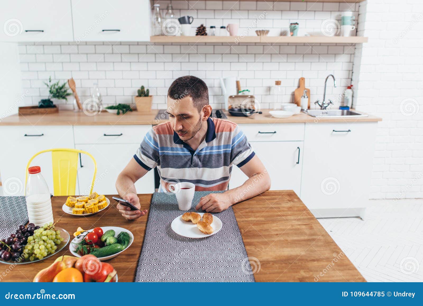 Man Eating Breakfast Using Smart Phone in Kitchen at Home. Stock Image ...