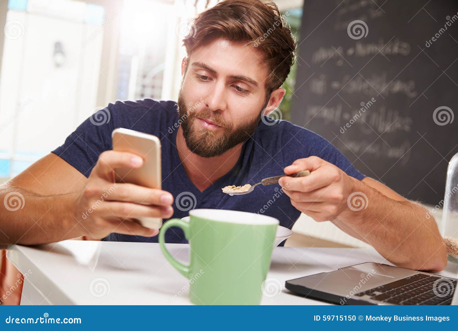 Man Eating Breakfast Whilst Using Mobile Phone and Laptop Stock Photo ...