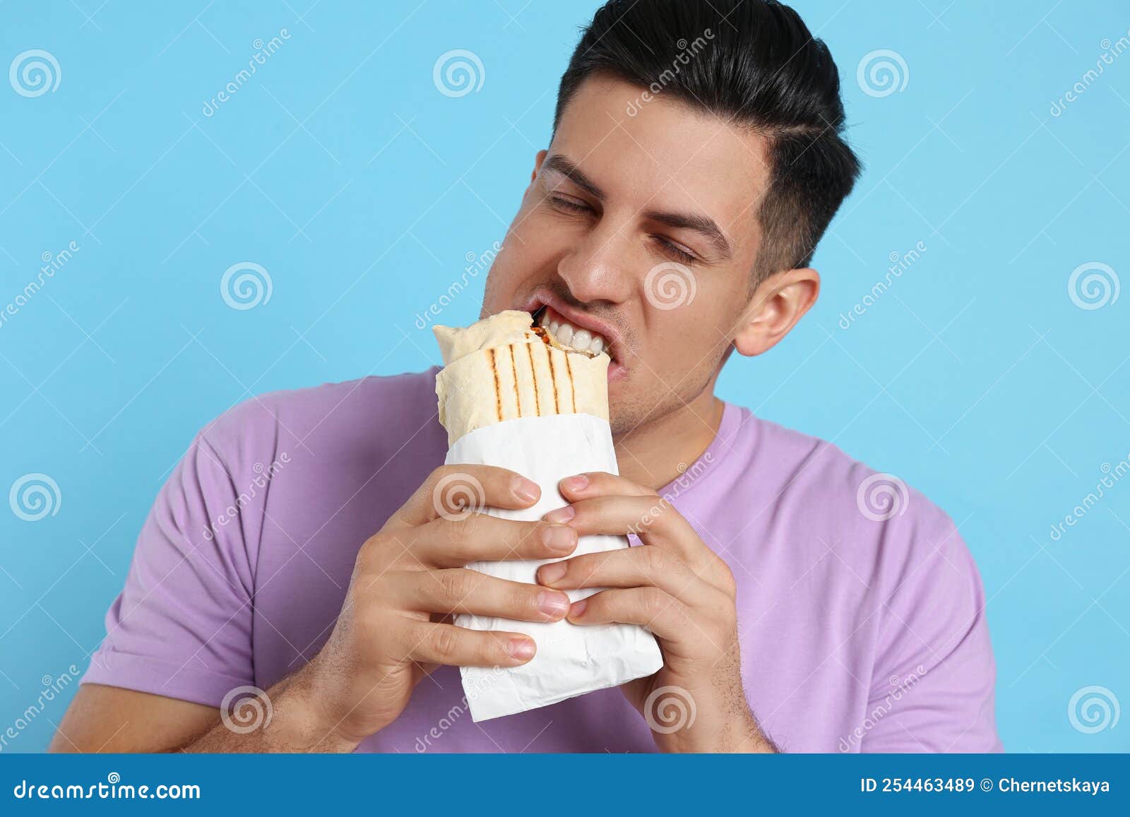 Man Eating Delicious Shawarma on Turquoise Background Stock Image ...