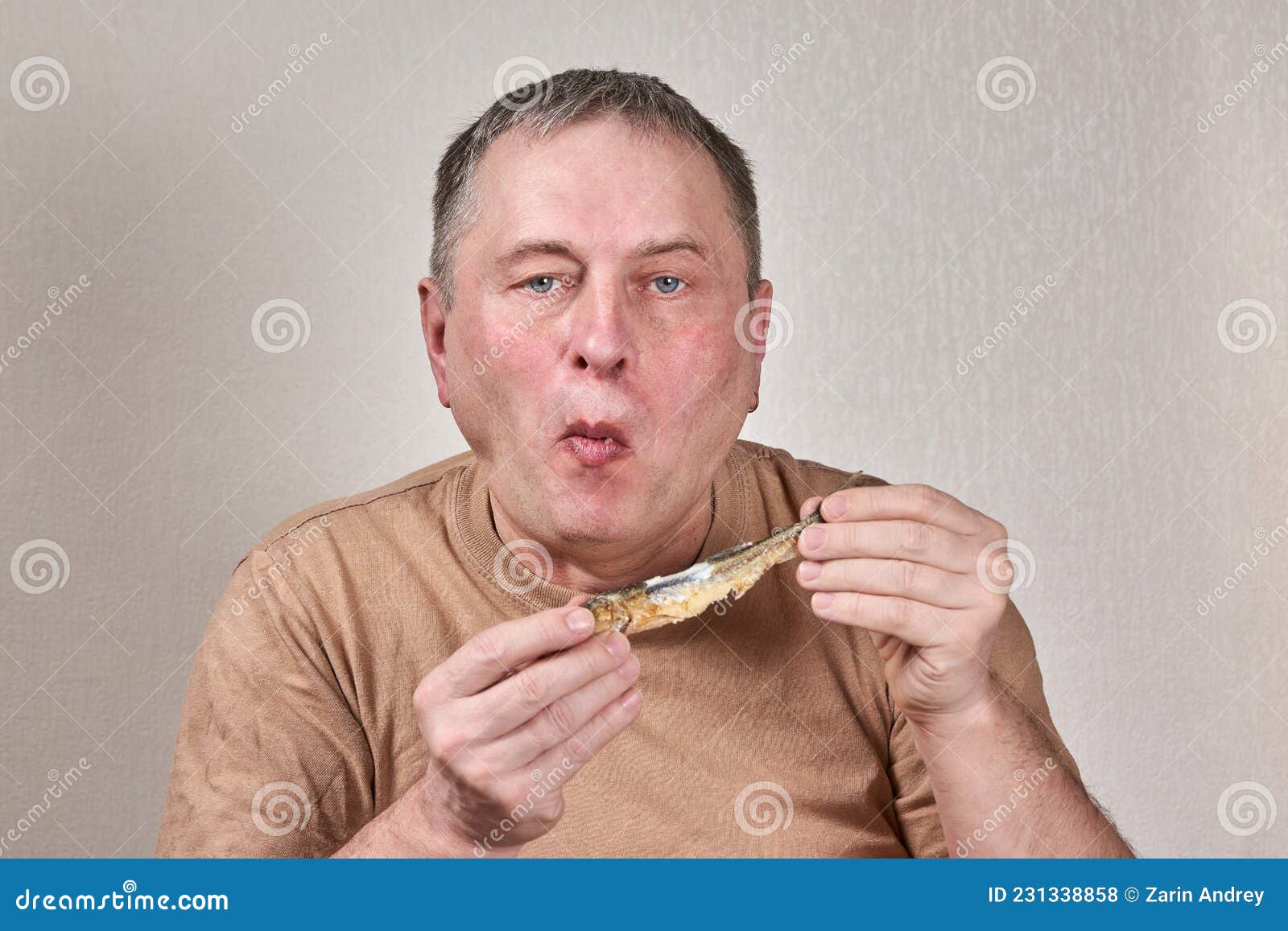Man Eating Fried Smelt Fish Holding Fish with Hands in Front of Face ...