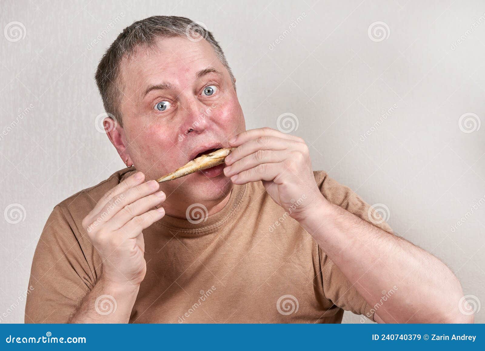 Man Eating Fried Smelt Fish Holding Fish with Hands in Front of Face ...