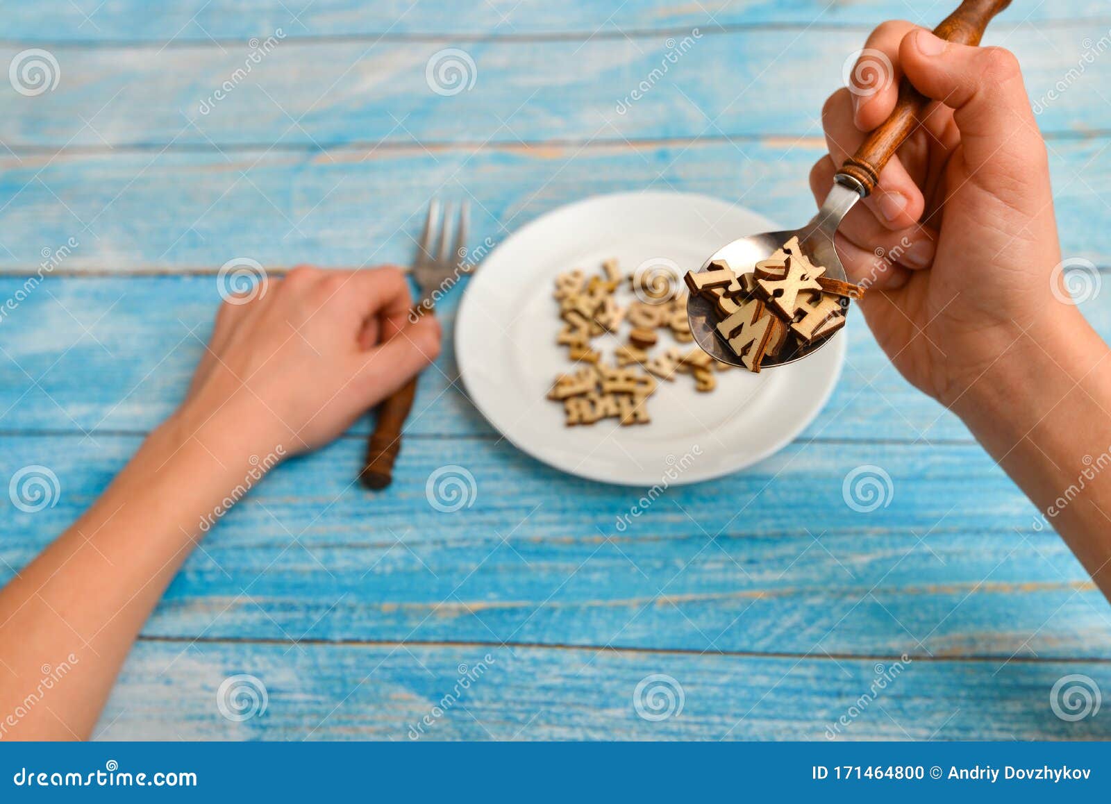 Man Eating Wooden Letters from a Spoon, on a Blue Wooden Background ...