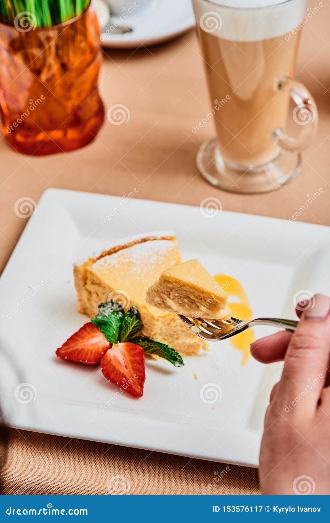 Man Eats Cheesecake with Strawberries on a White Plate on the Table in ...