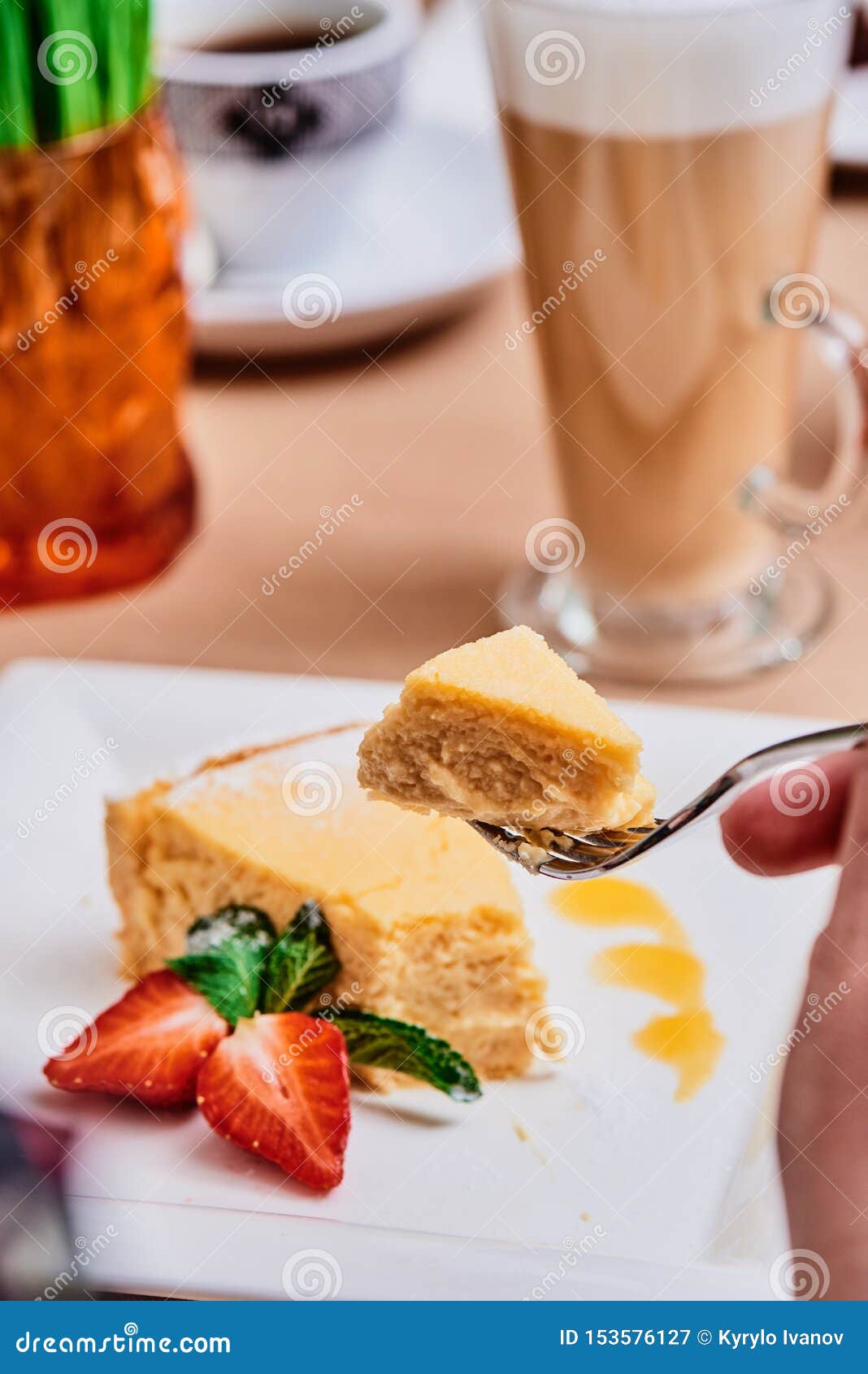 Man Eats Cheesecake with Strawberries on a White Plate on the Table in ...