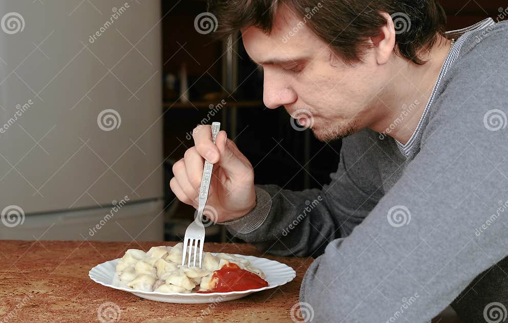 Man Eats Dumplings with a Fork, Putting Them into Tomato Sauce in the ...