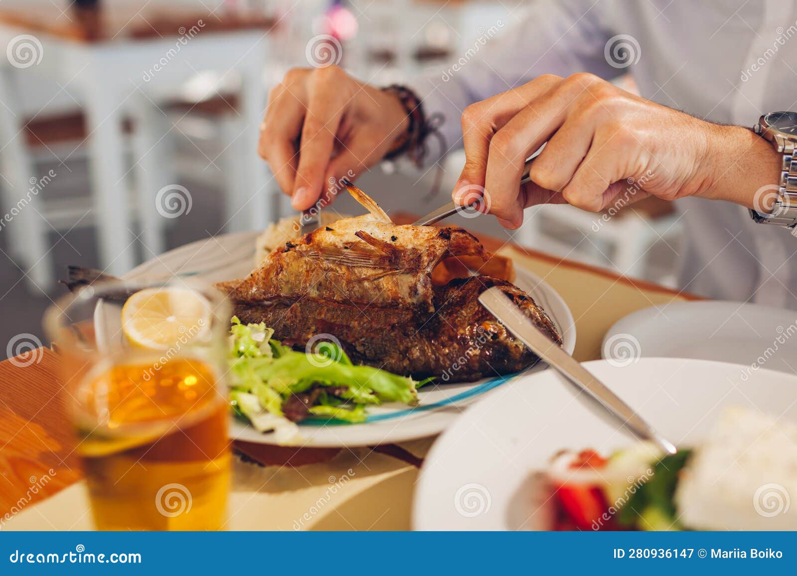 Man Eats Fish with Vegetables in Outdoors Restaurant. Fresh Seafood ...