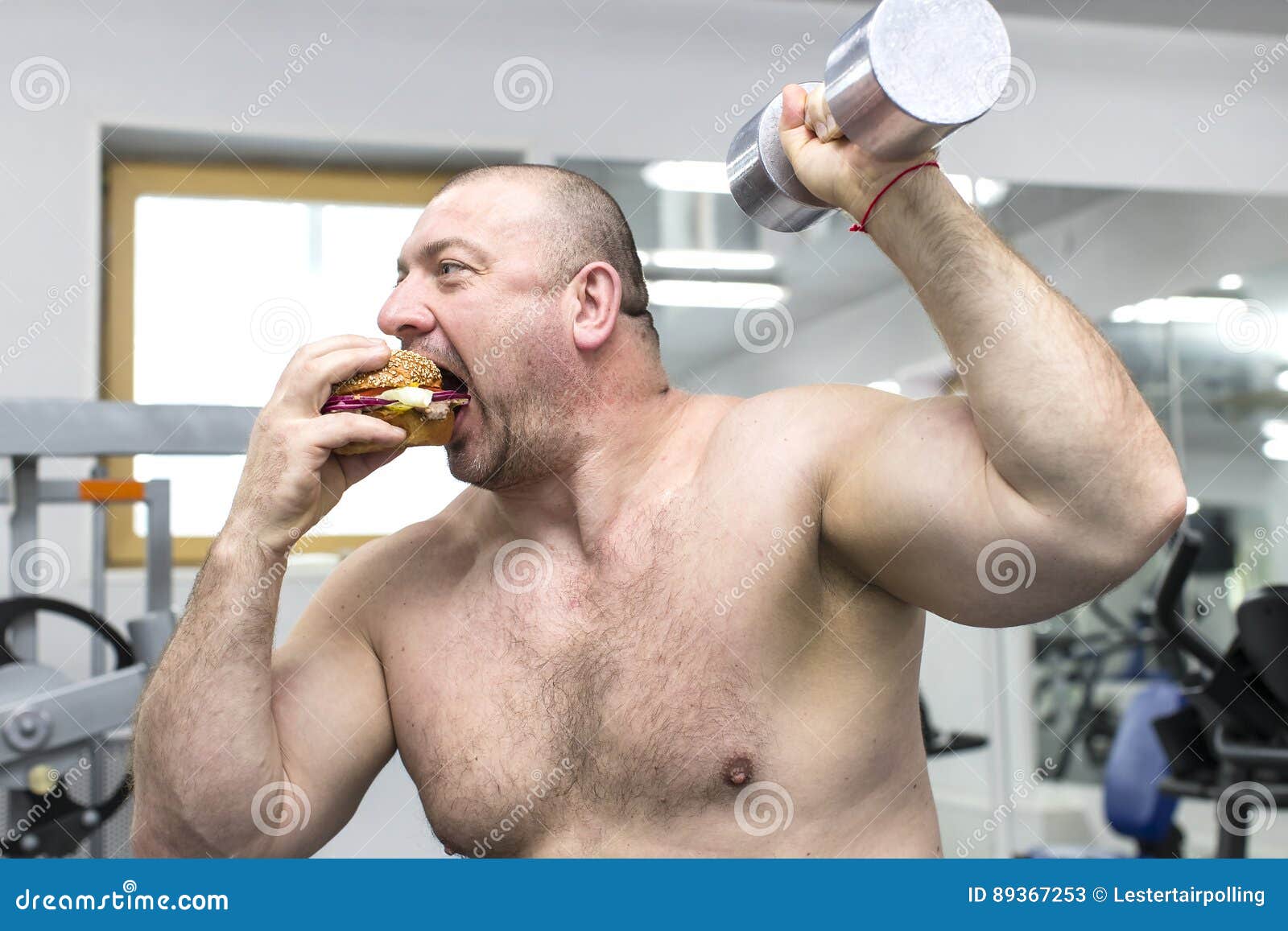 Man Eats a Hamburger with Meat and Cheese in the Gym Stock Image ...