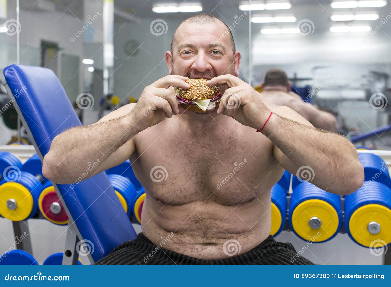 Man Eats a Hamburger with Meat and Cheese in the Gym Stock Photo ...