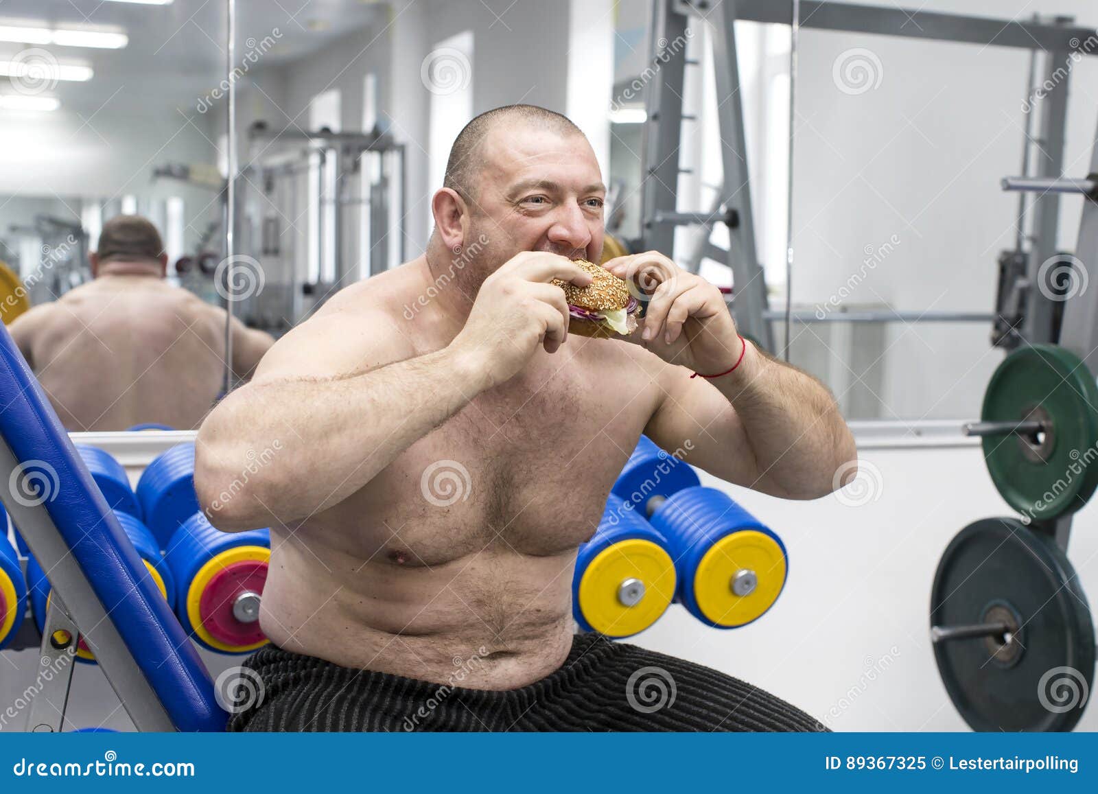 Man Eats a Hamburger with Meat and Cheese in the Gym Stock Image ...