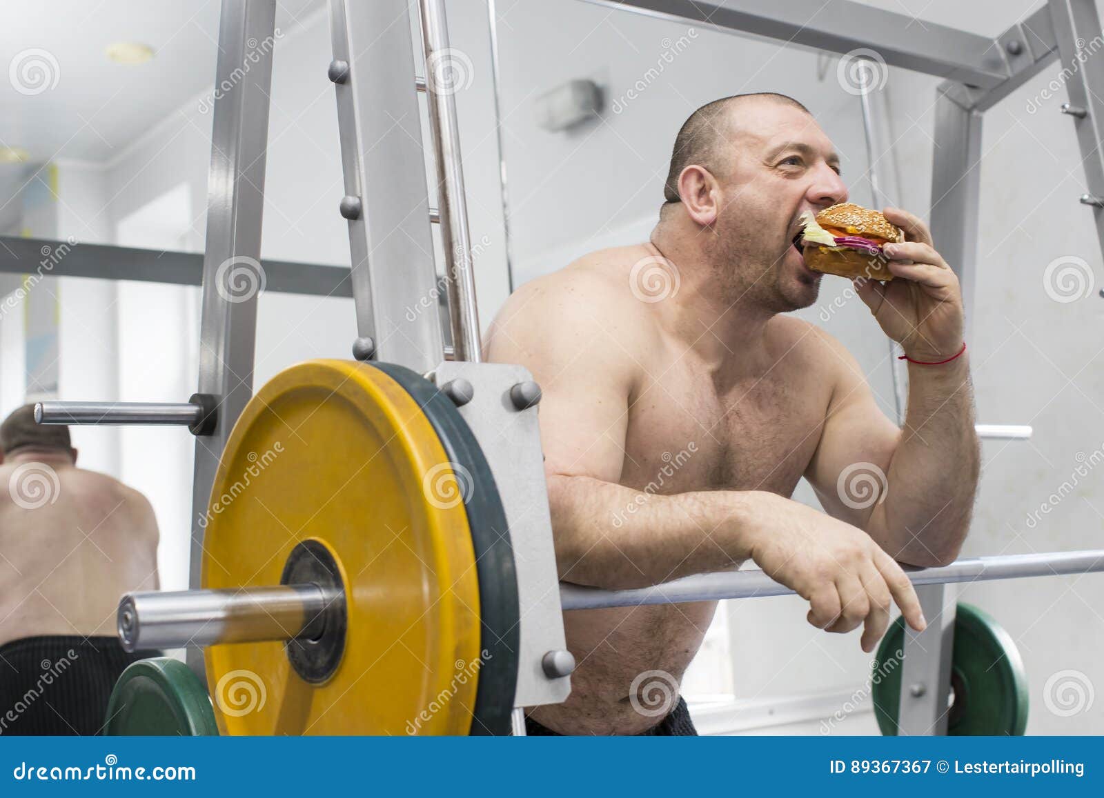 Man Eats a Hamburger with Meat and Cheese in the Gym Stock Image ...