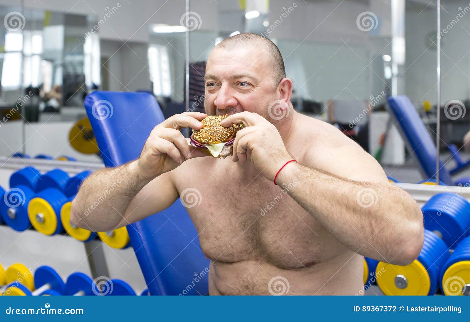 Man Eats a Hamburger with Meat and Cheese in the Gym Stock Photo ...