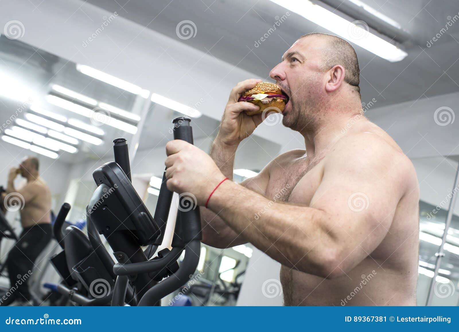 Man Eats a Hamburger with Meat and Cheese in the Gym Stock Image ...