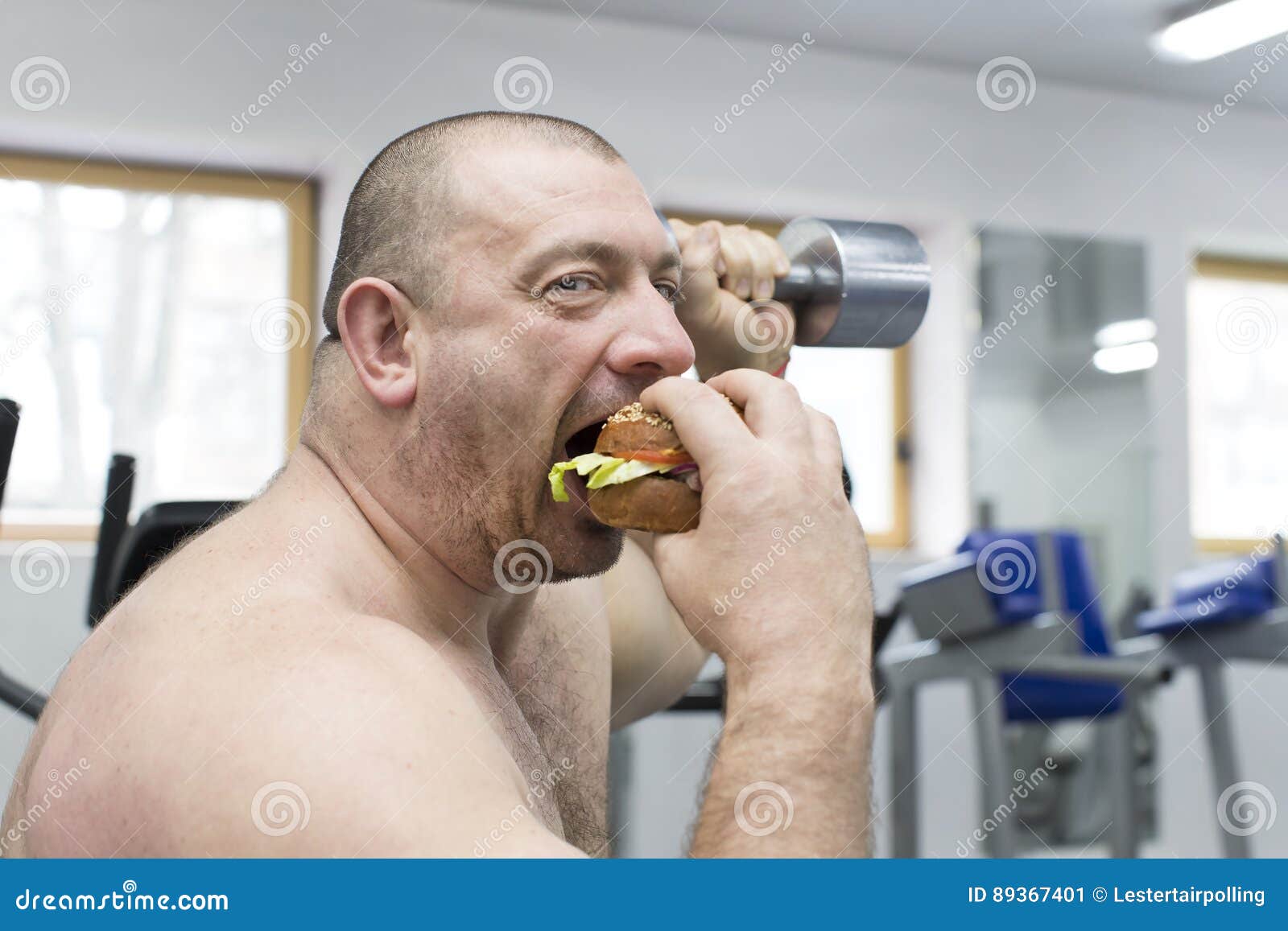 Man Eats a Hamburger with Meat and Cheese in the Gym Stock Image ...