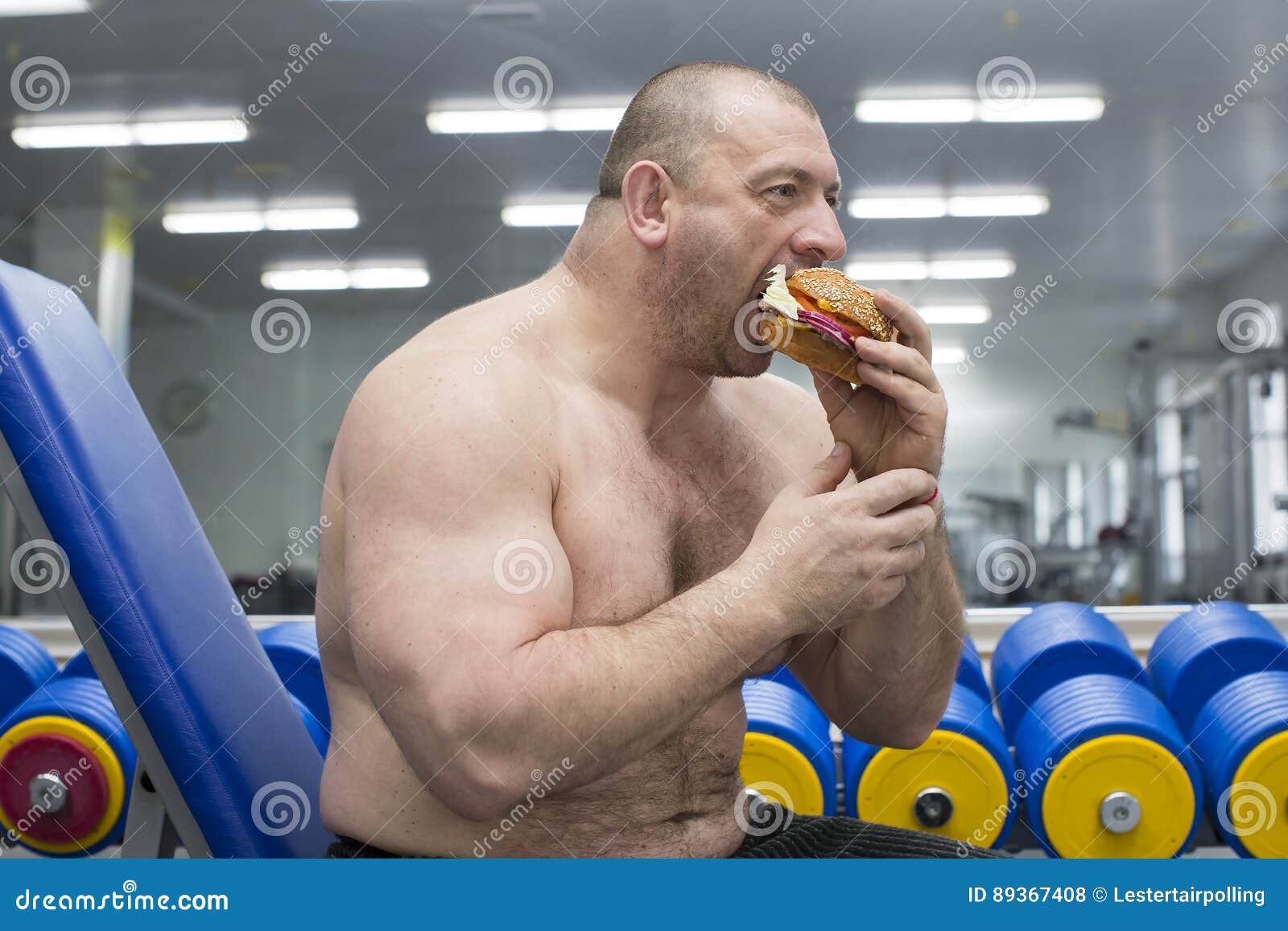 Man Eats a Hamburger with Meat and Cheese in the Gym Stock Photo ...