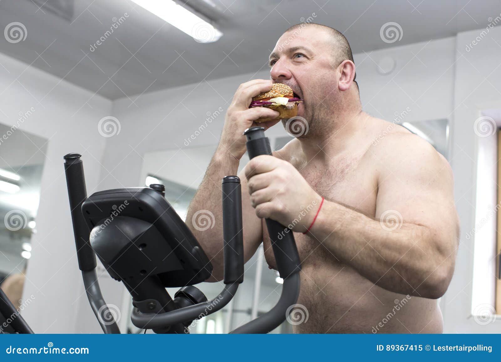 Man Eats a Hamburger with Meat and Cheese in the Gym Stock Image ...
