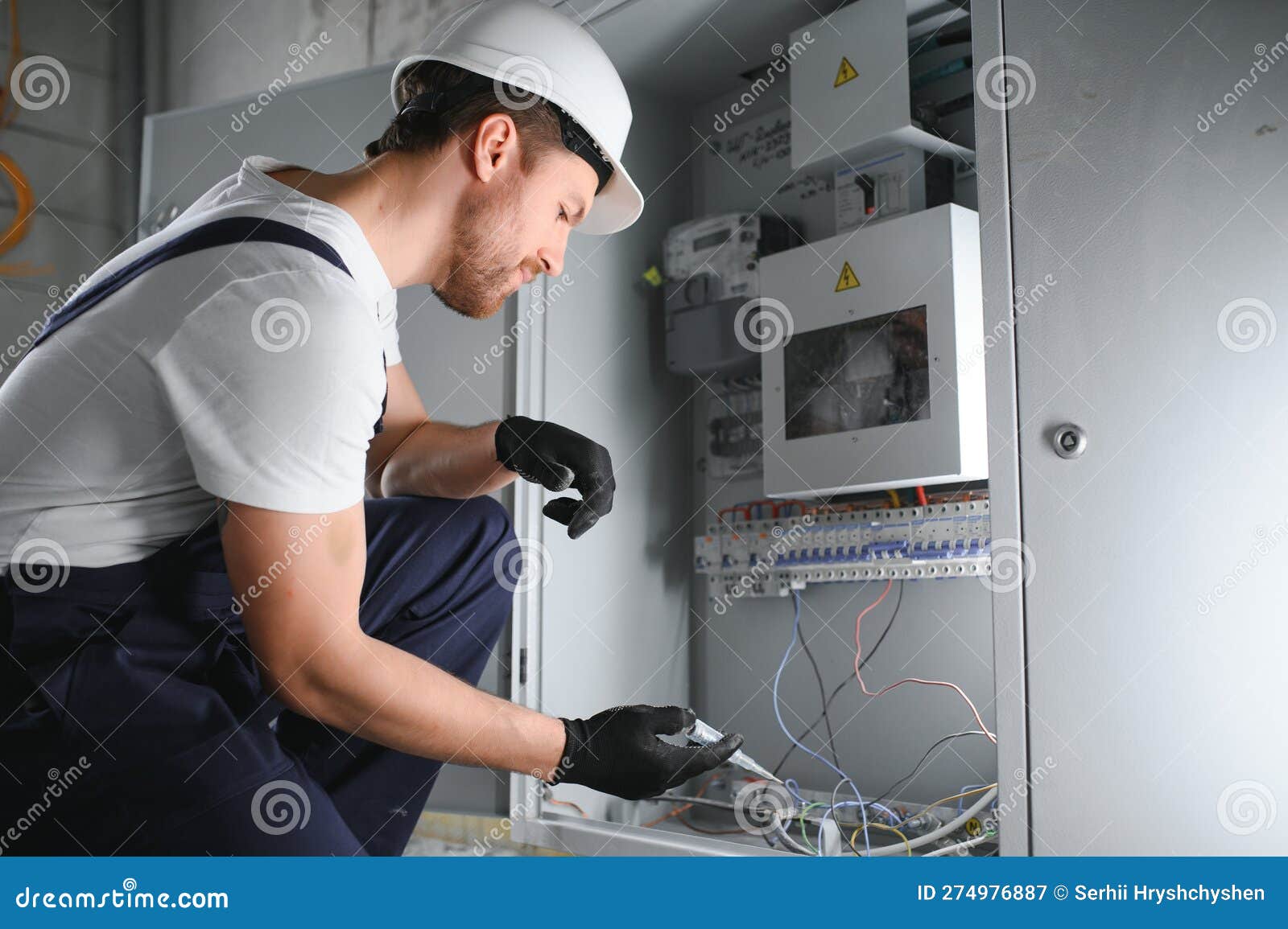Man, an Electrical Technician Working in a Switchboard with Fuses ...