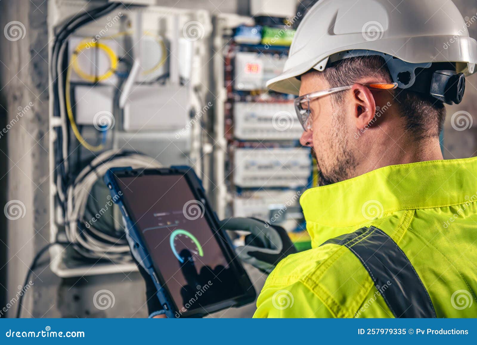 Man, an Electrical Technician Working in a Switchboard with Fuses, Uses a Tablet. Stock Image ...