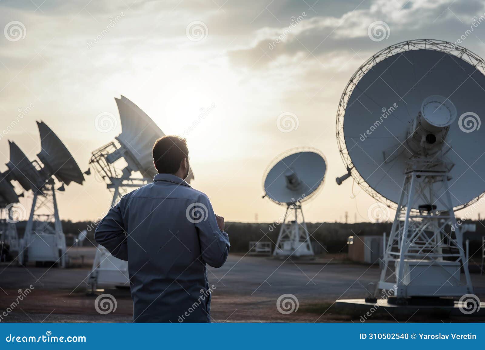 Man in Engineering Attire Facing Multiple Satellite Dishes in a ...