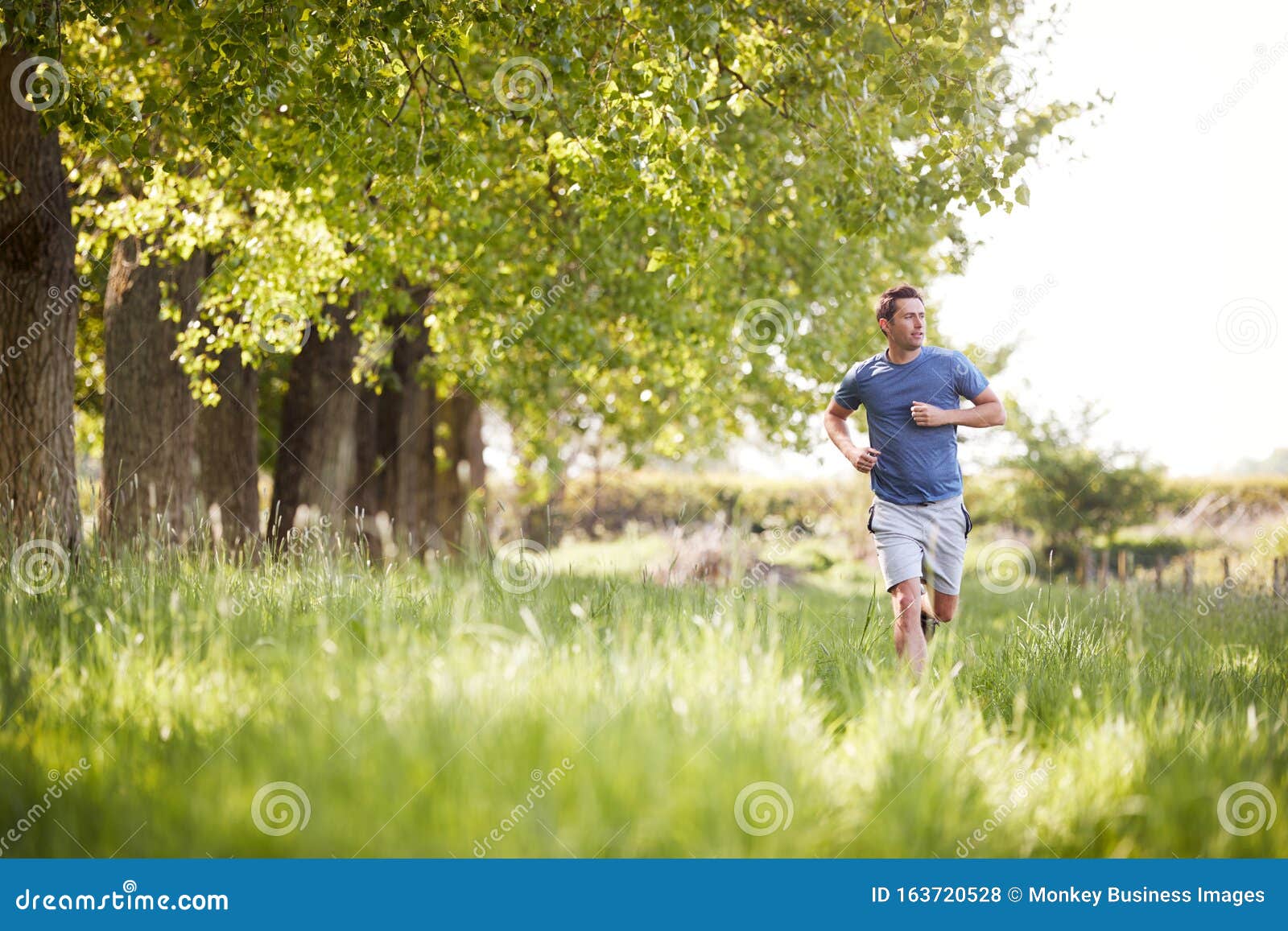 Man Exercising Running through Countryside Field Stock Photo - Image of ...