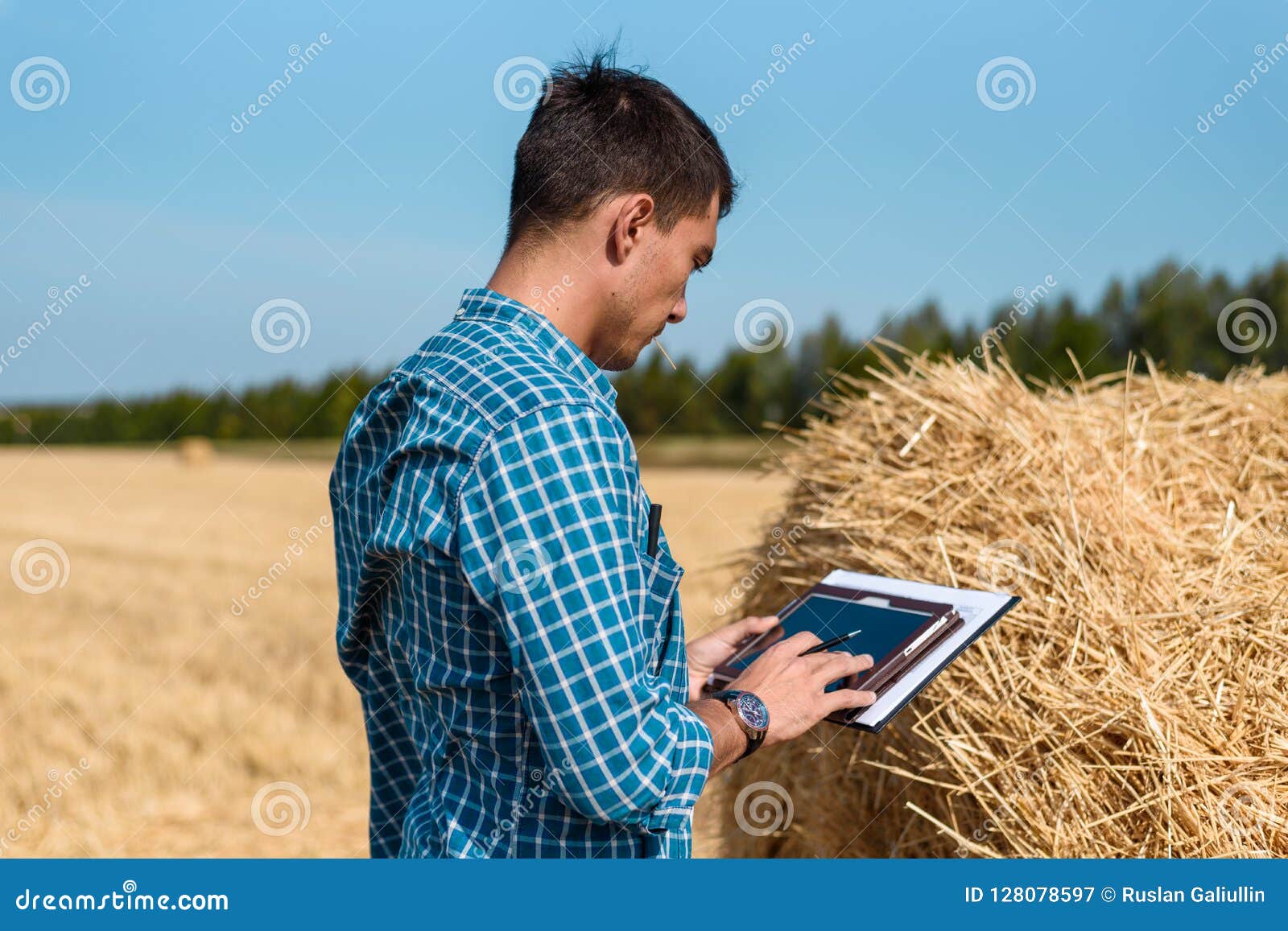 Man Farmer Uses a Tablet in the Field Next To a Haystack Stock Image ...