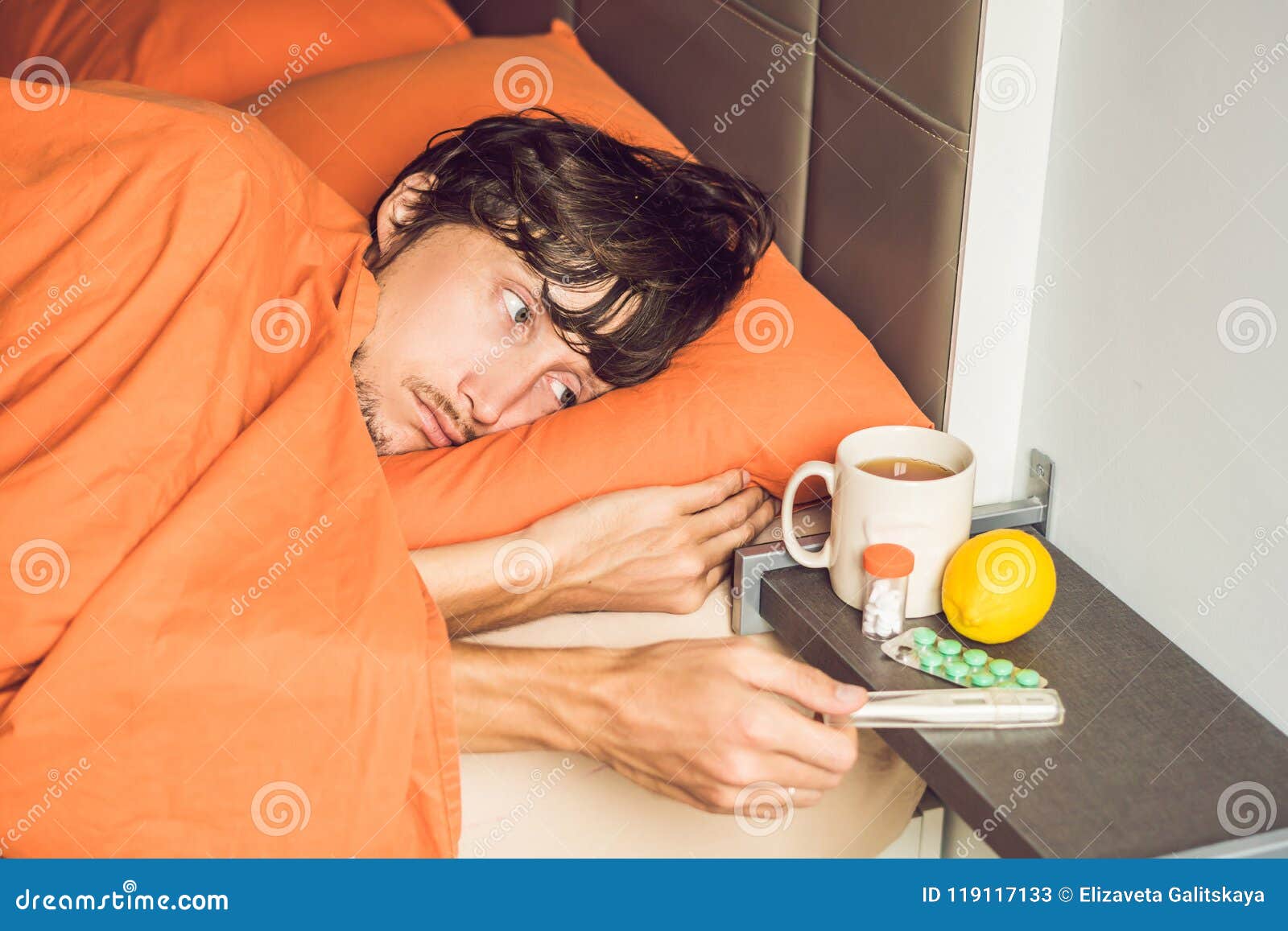 Man Feeling Cold, Lying in the Bed and Drinks Tea and Measures T Stock ...