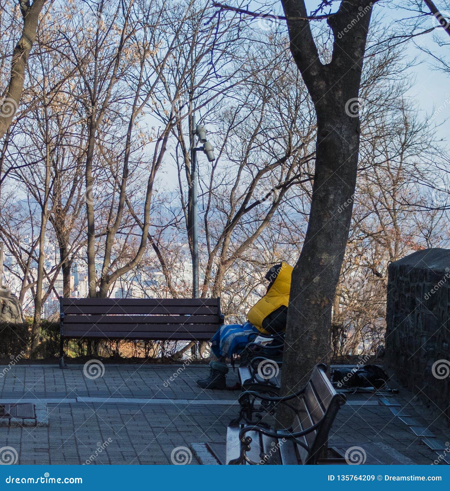 A Man Feeling Cold Sitting on the Bench Relaxing on His Jacket ...