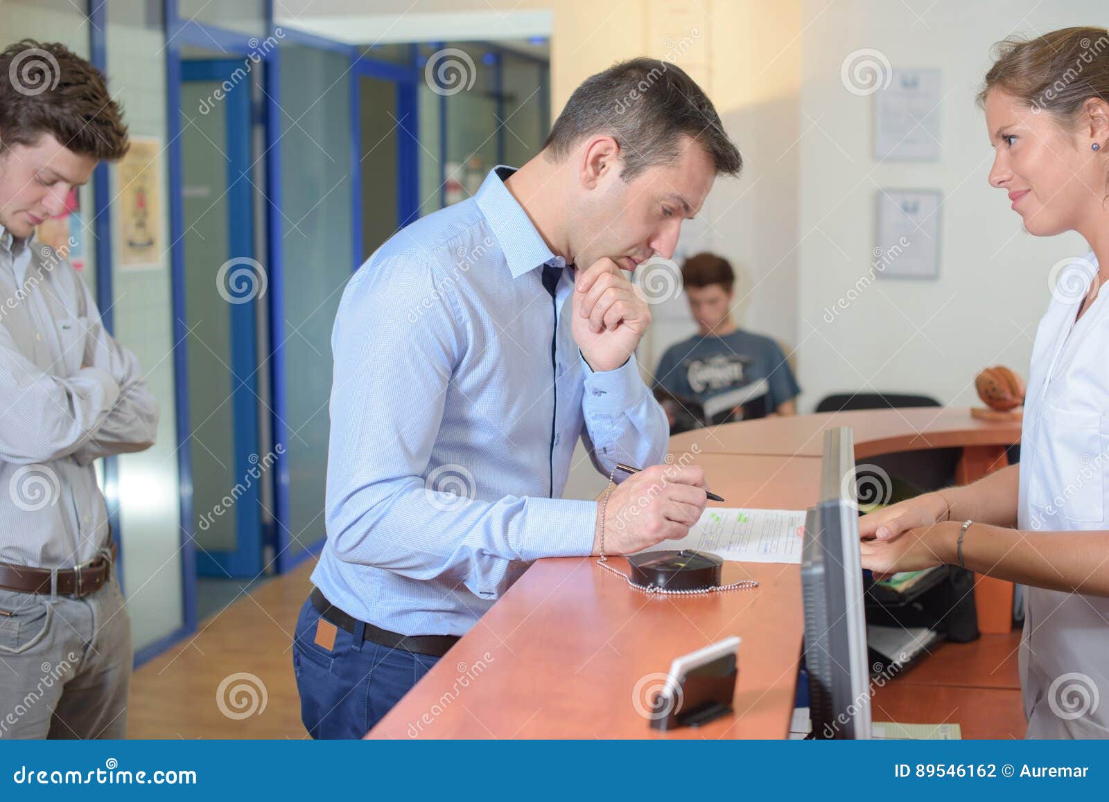 Man Filling Out Form Stood at Reception Desk Stock Photo - Image of ...
