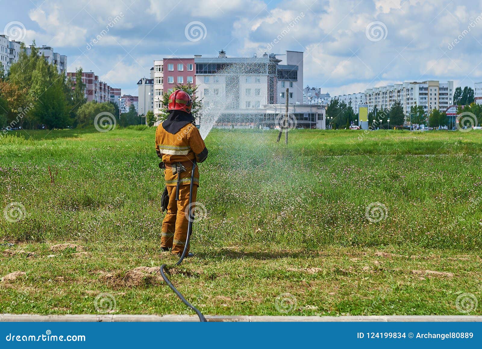 A Man Firefighter from a Fire Hose Watering the Grass Stock Photo ...