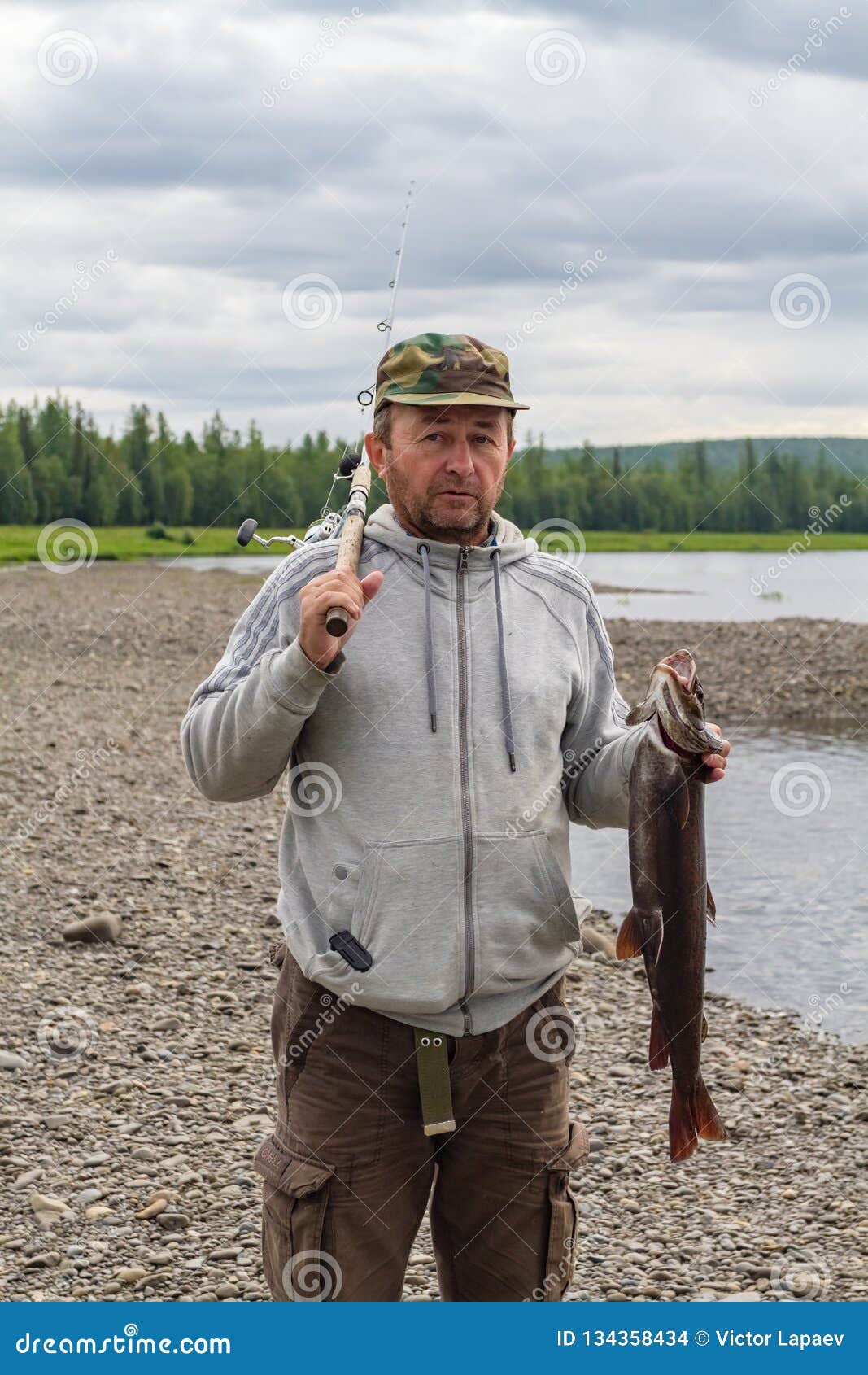 A Man with a Fish on a Pebble Beach. Siberia, Russia (Rev Stock Photo ...